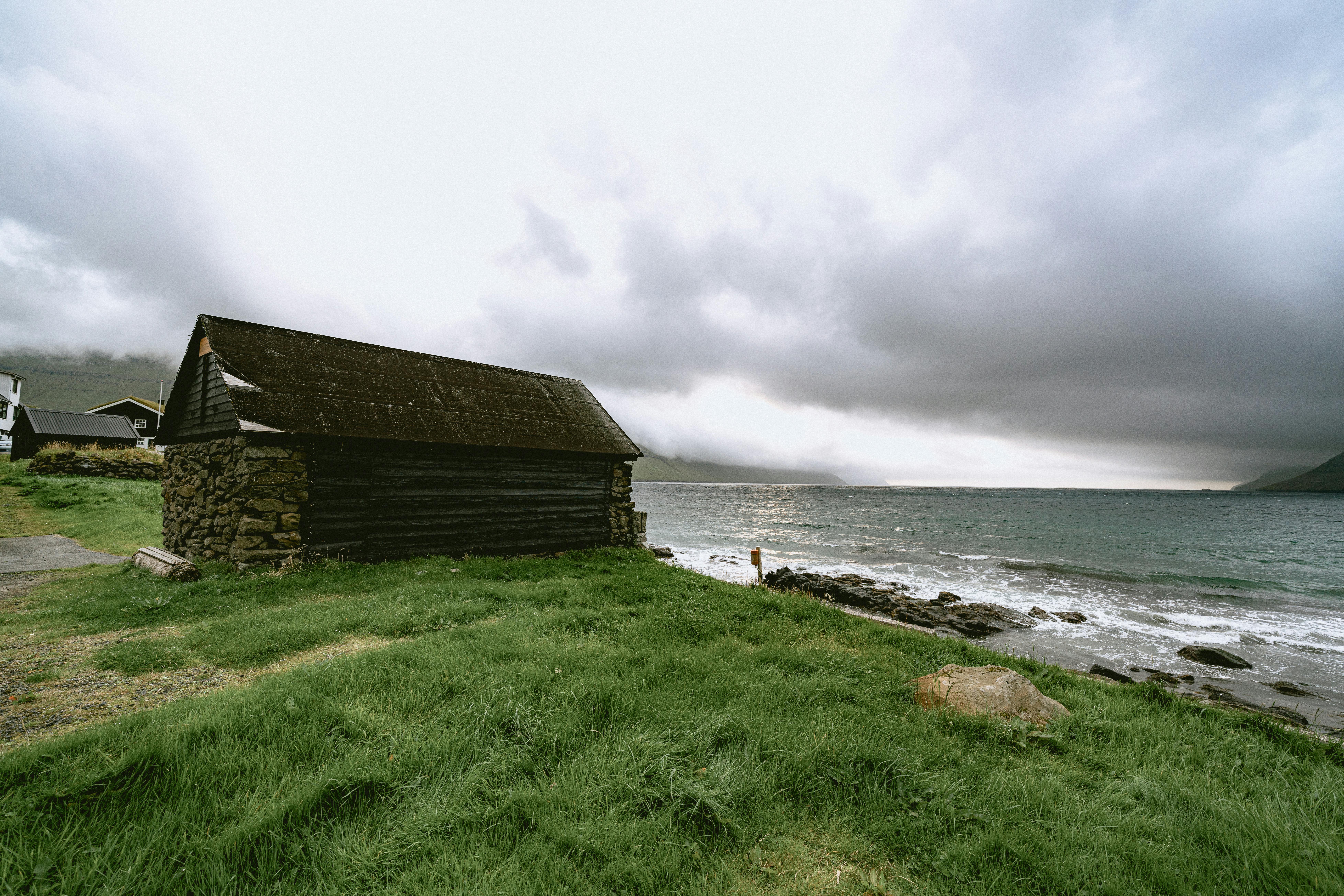 Farmhouse on a Lakeshore under a Stormy Sky · Free Stock Photo