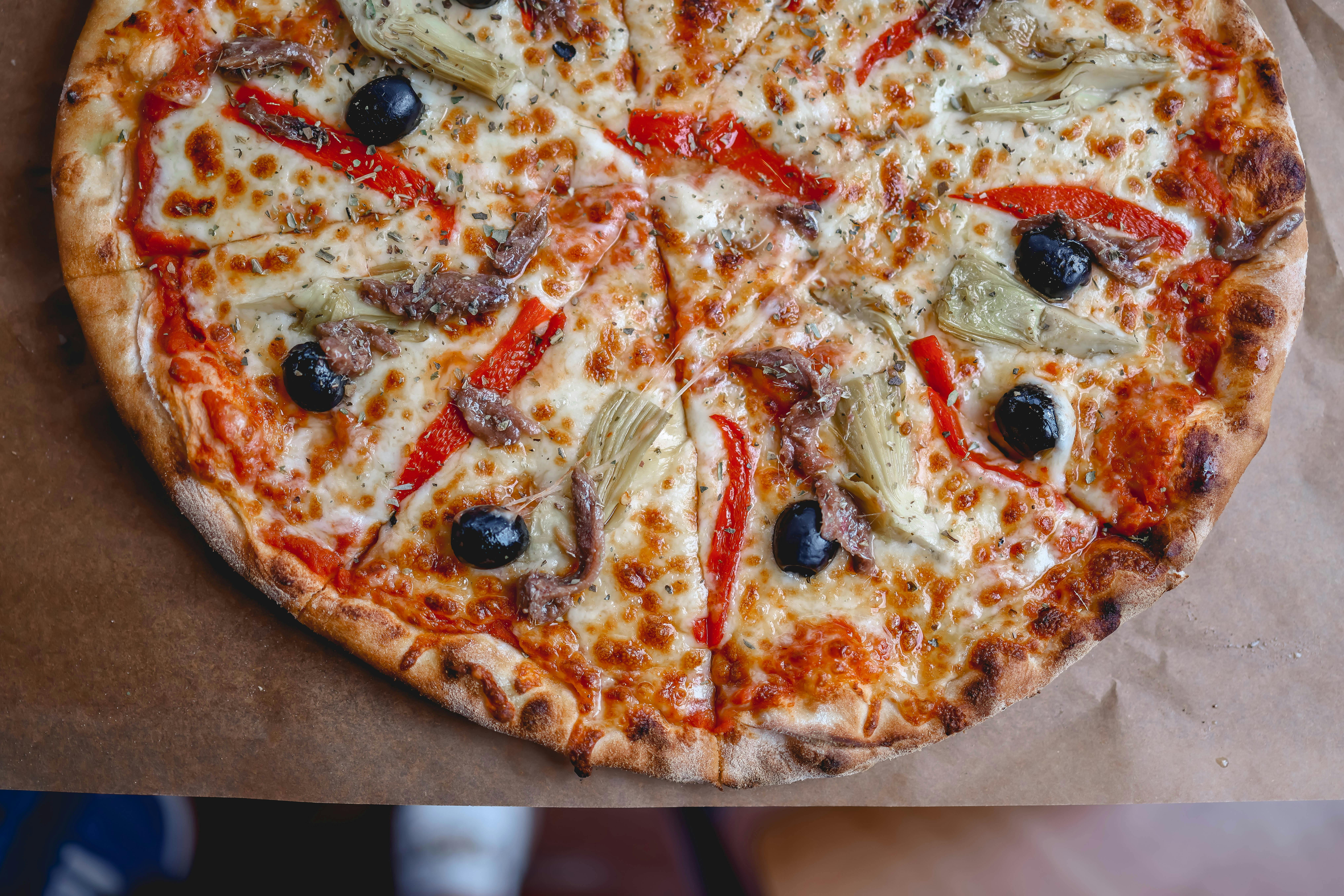 Top View of a Pizza with Black Olives and Red Peppers · Free Stock Photo
