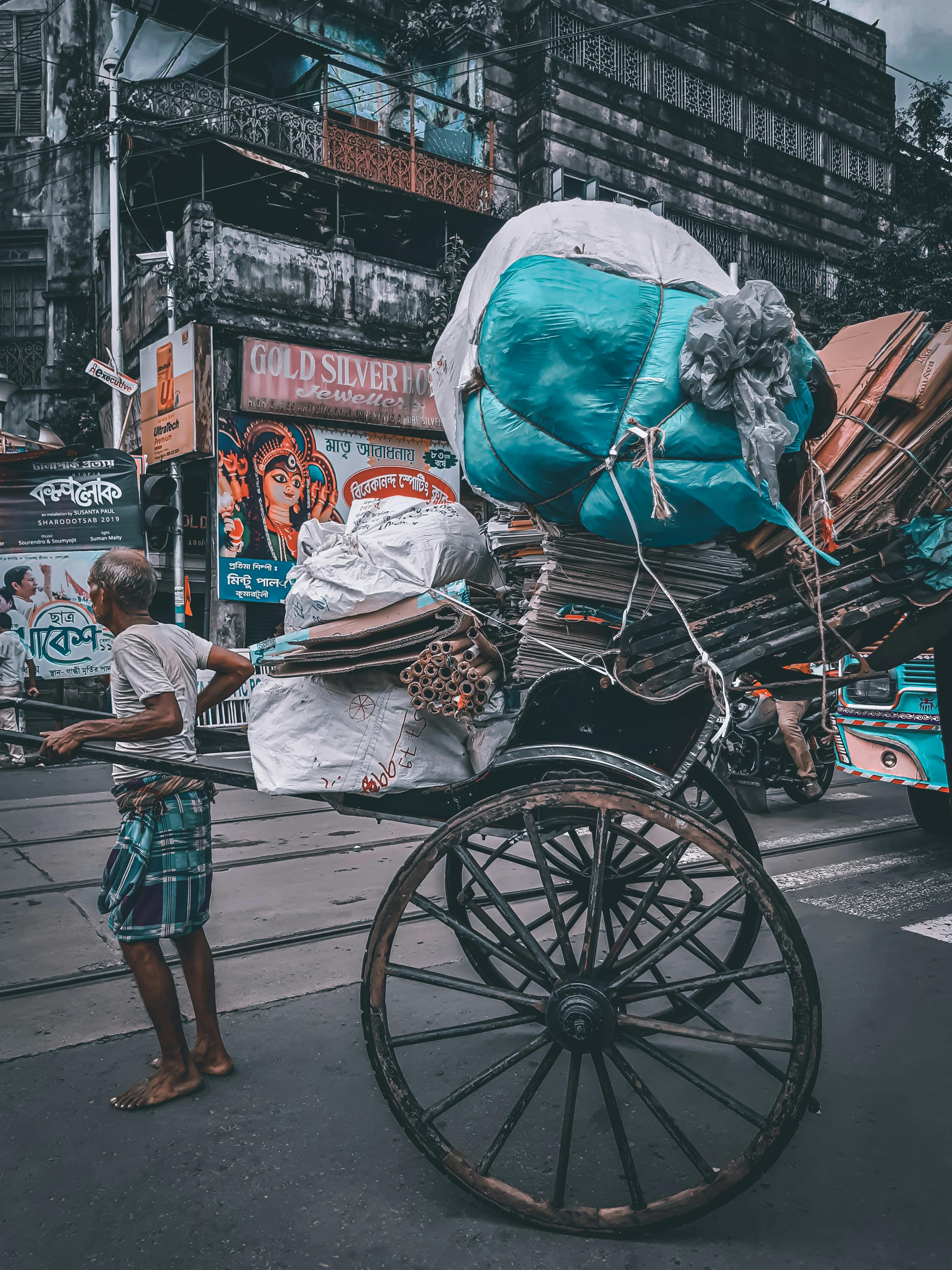 Man on the Street Pulling a Large Cart with Bags · Free Stock Photo