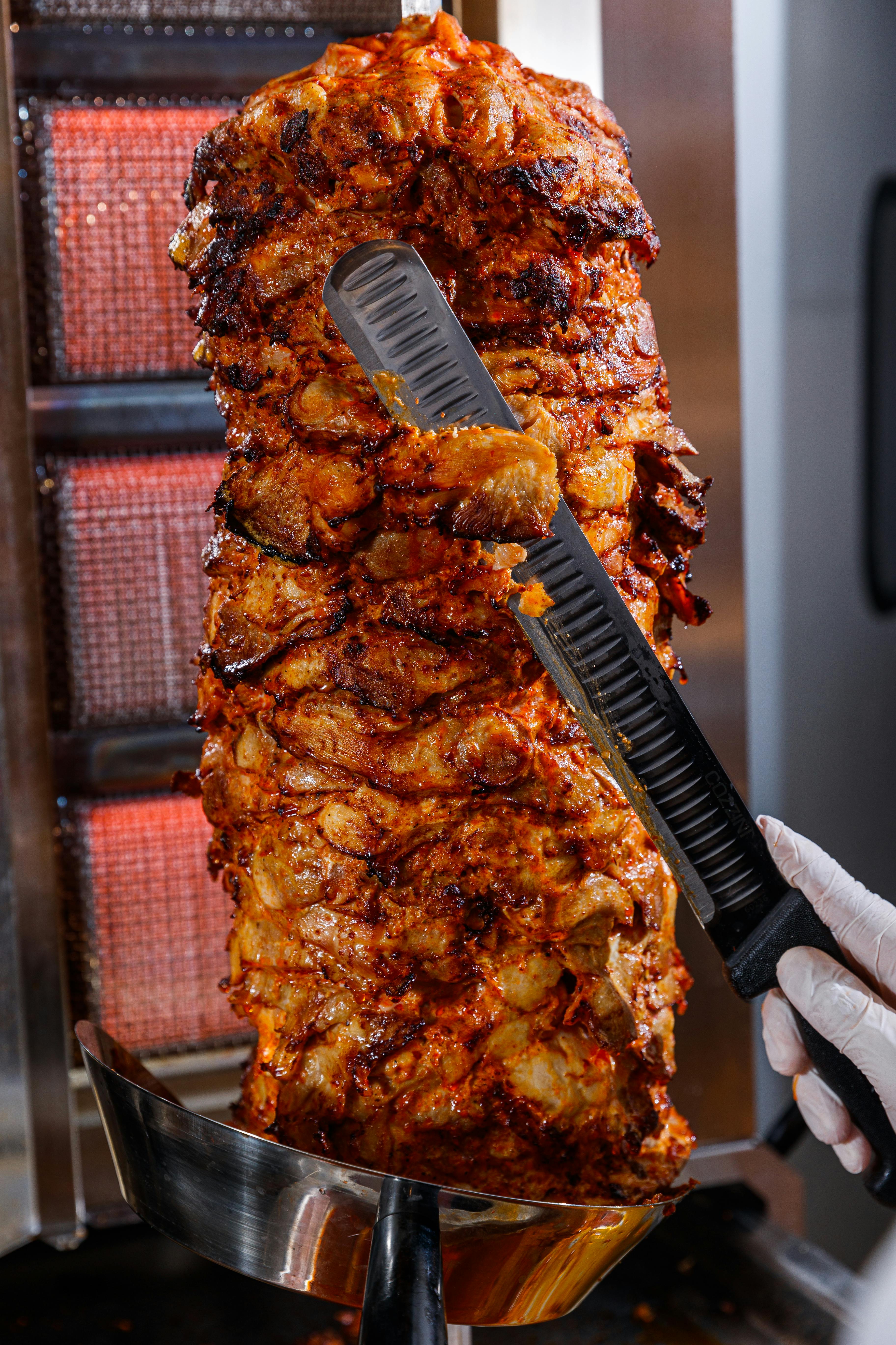 Cook Cutting Meat on a Rotating Spit to Prepare Shawarma · Free Stock Photo