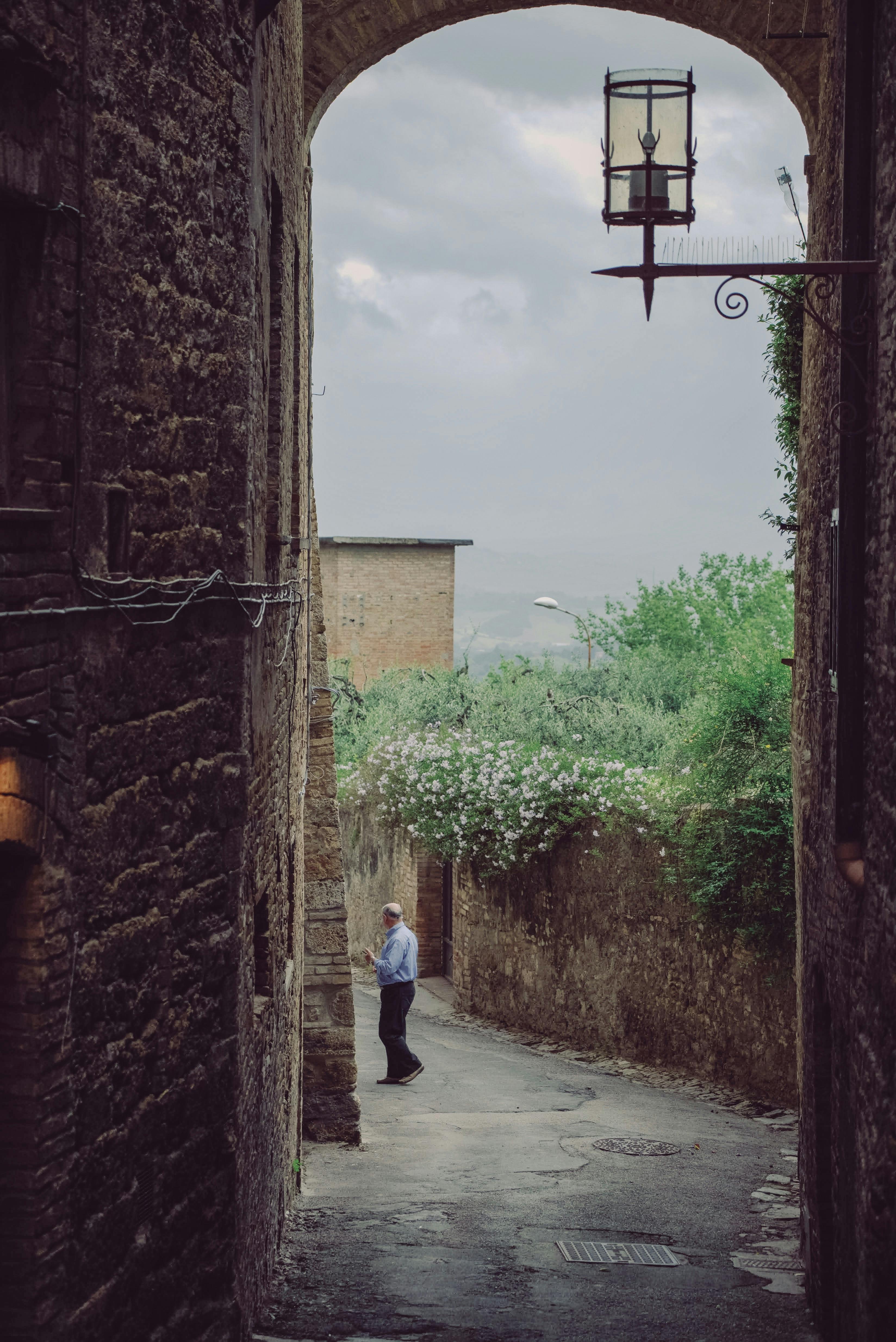 Man Sitting on Bridge Wall in Town · Free Stock Photo