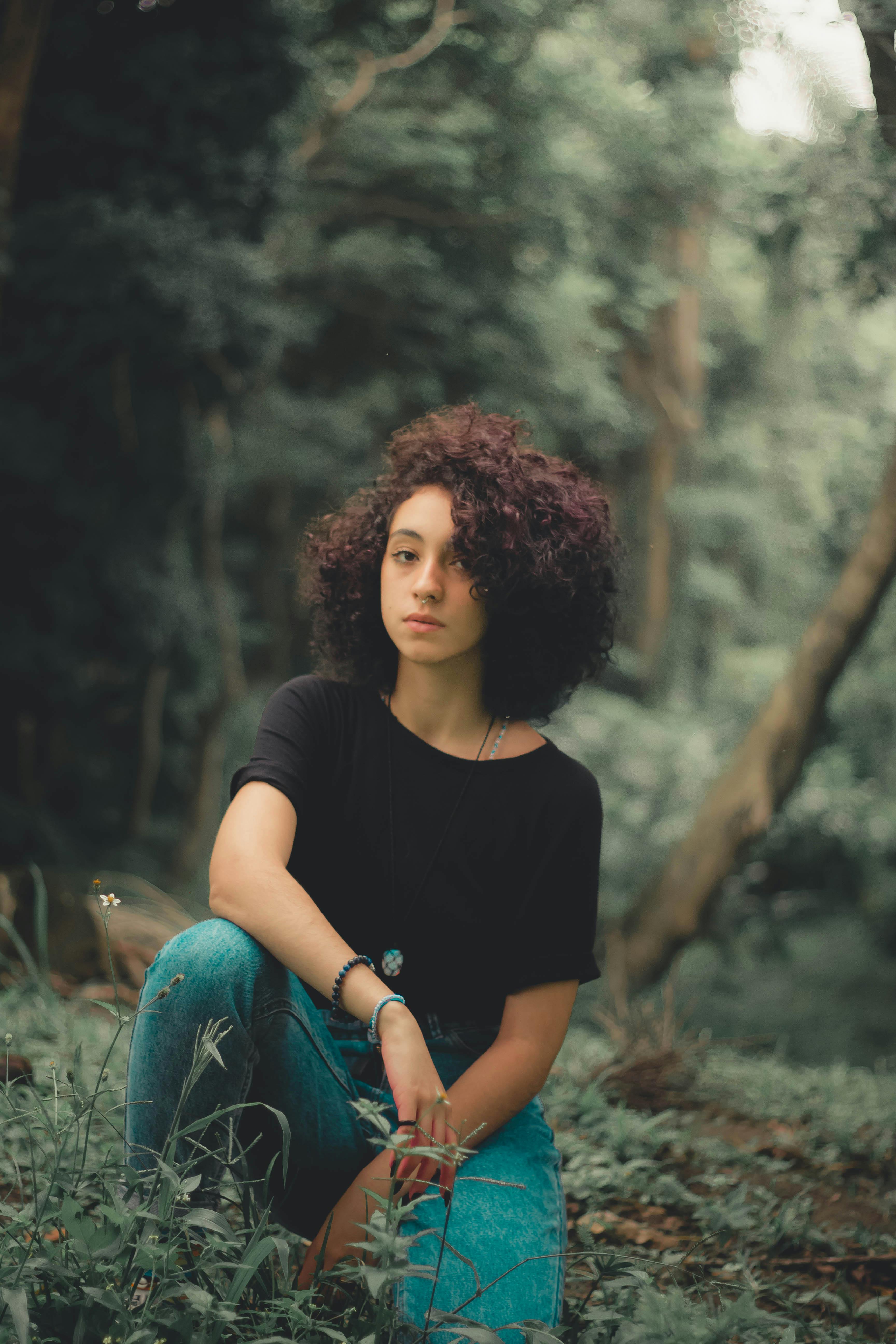 Portrait of Curly Haired Woman in Jeans Crouching · Free Stock Photo