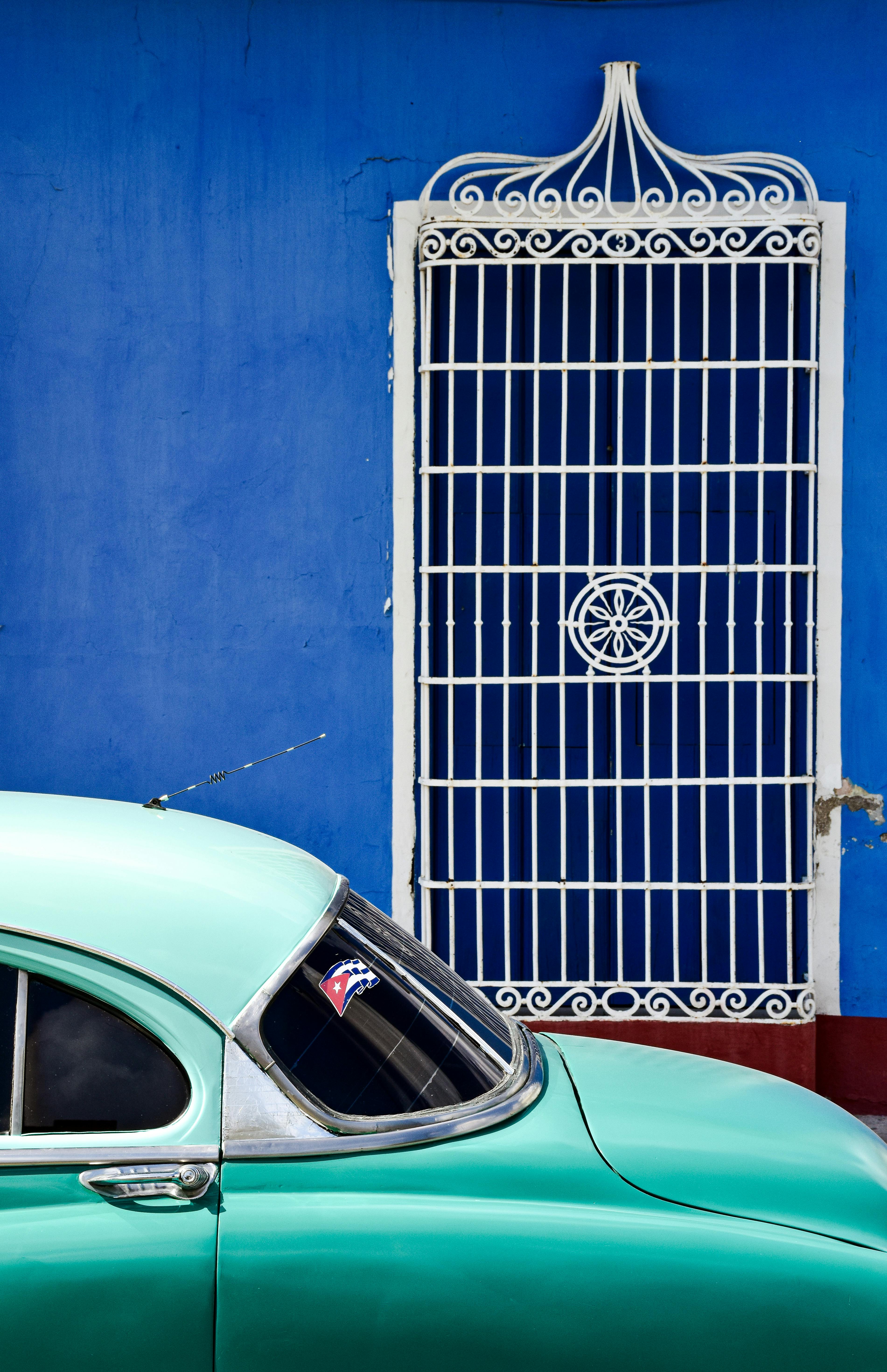 Window with White Metal Bars in Front of Old Green Car · Free Stock Photo