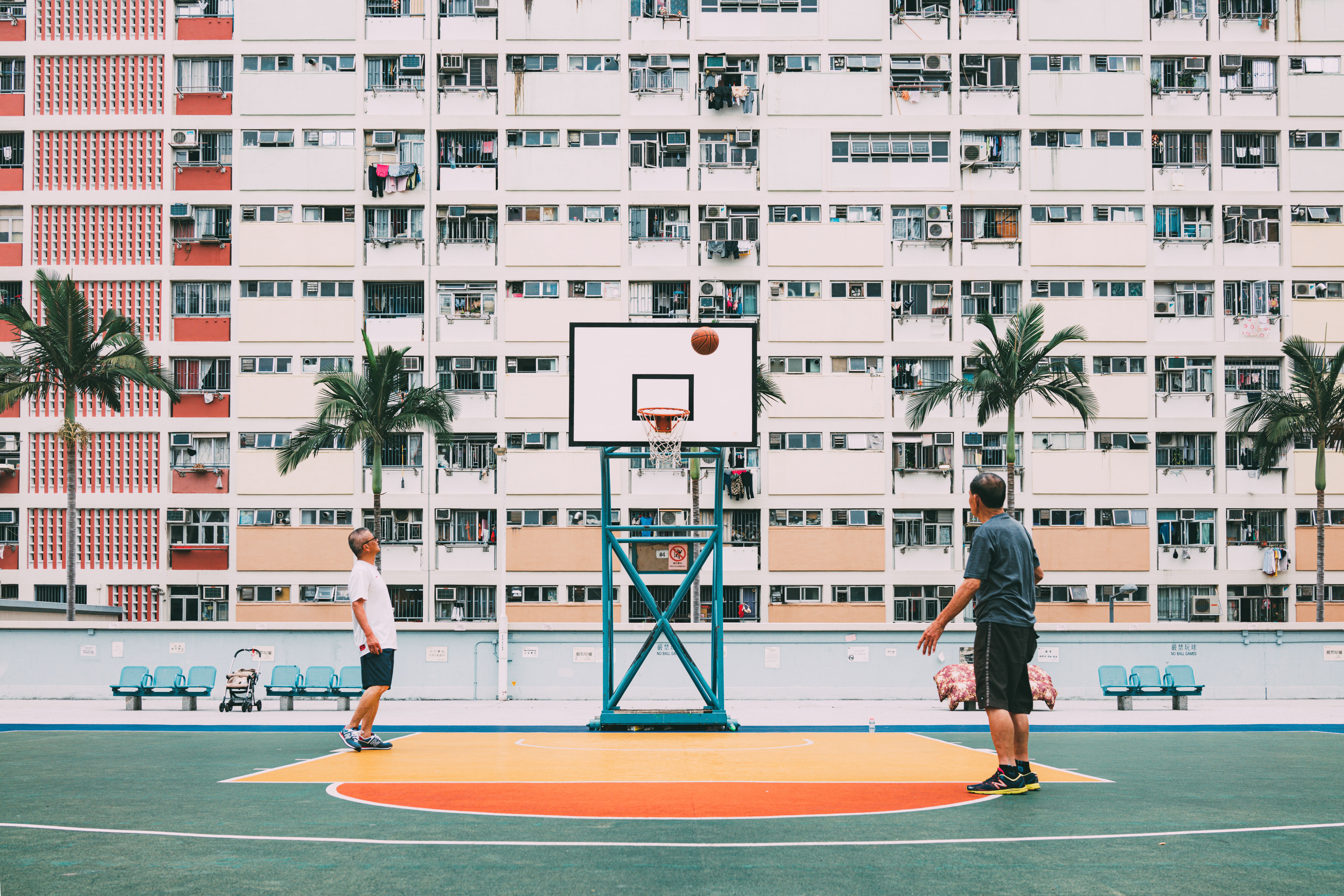 Men Playing Basketball on a Court between Residential Buildings in City ...
