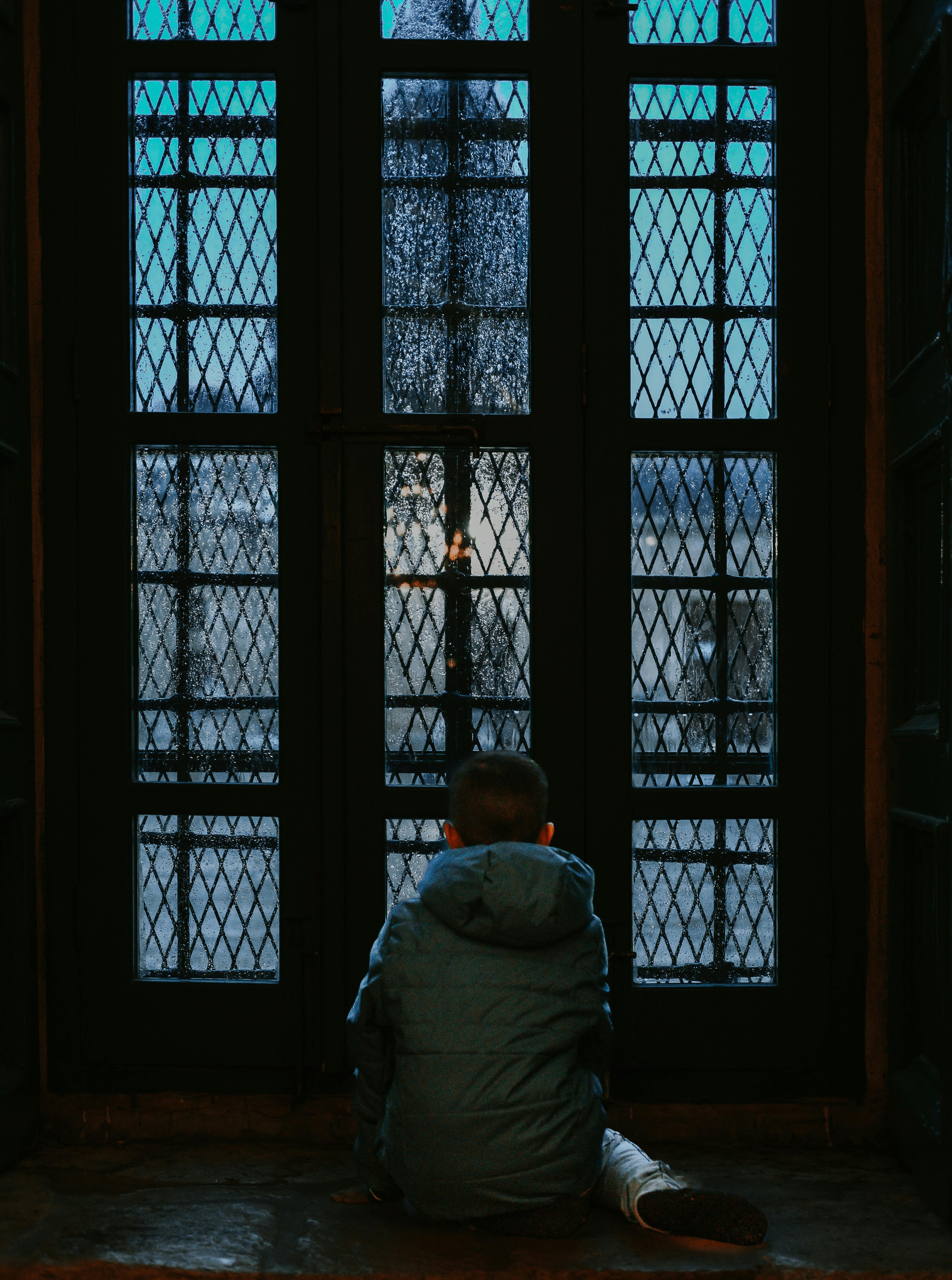 A child sitting in front of a window looking out · Free Stock Photo