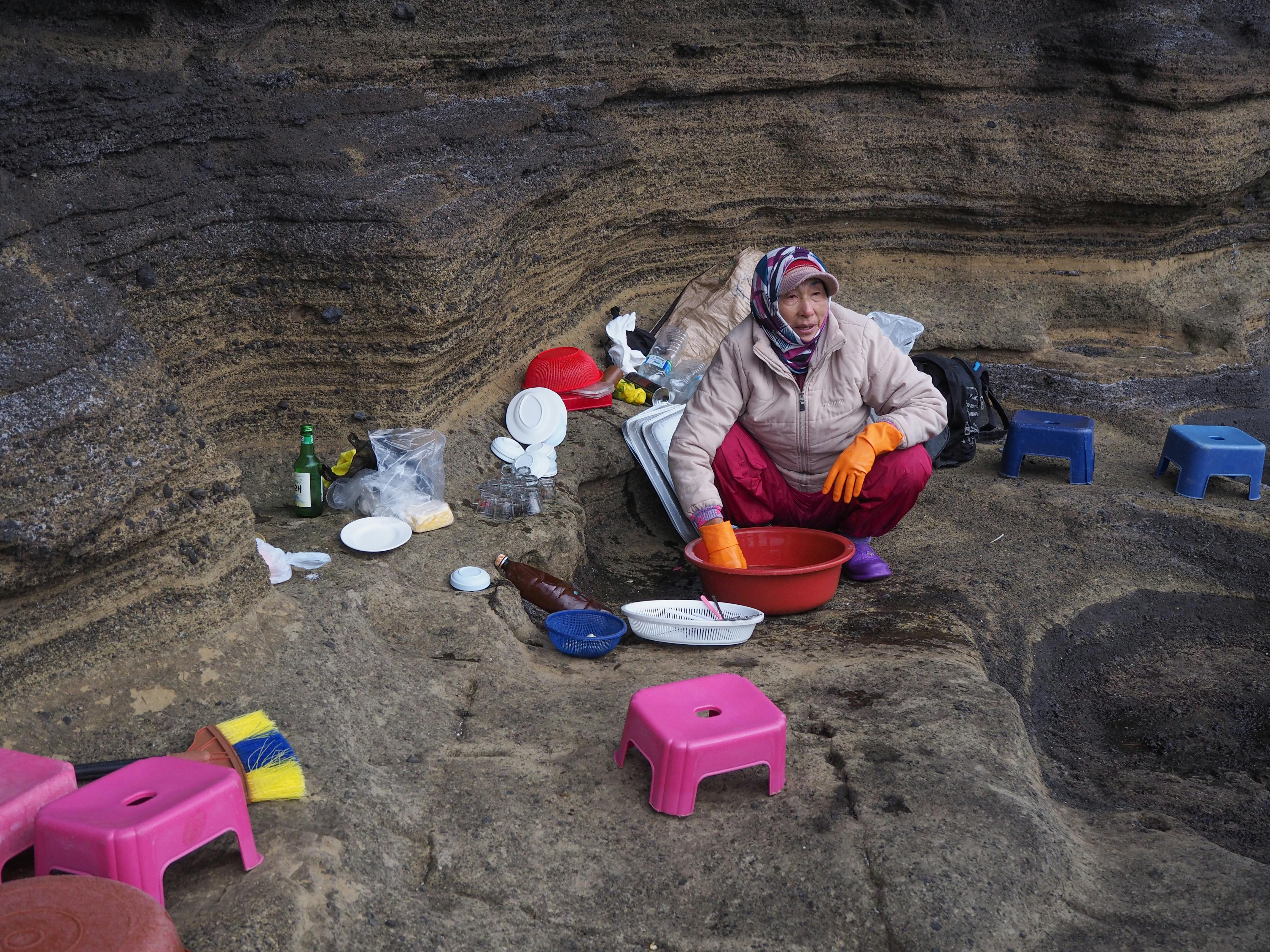 Elderly Woman Crouching on Rock Shelf · Free Stock Photo