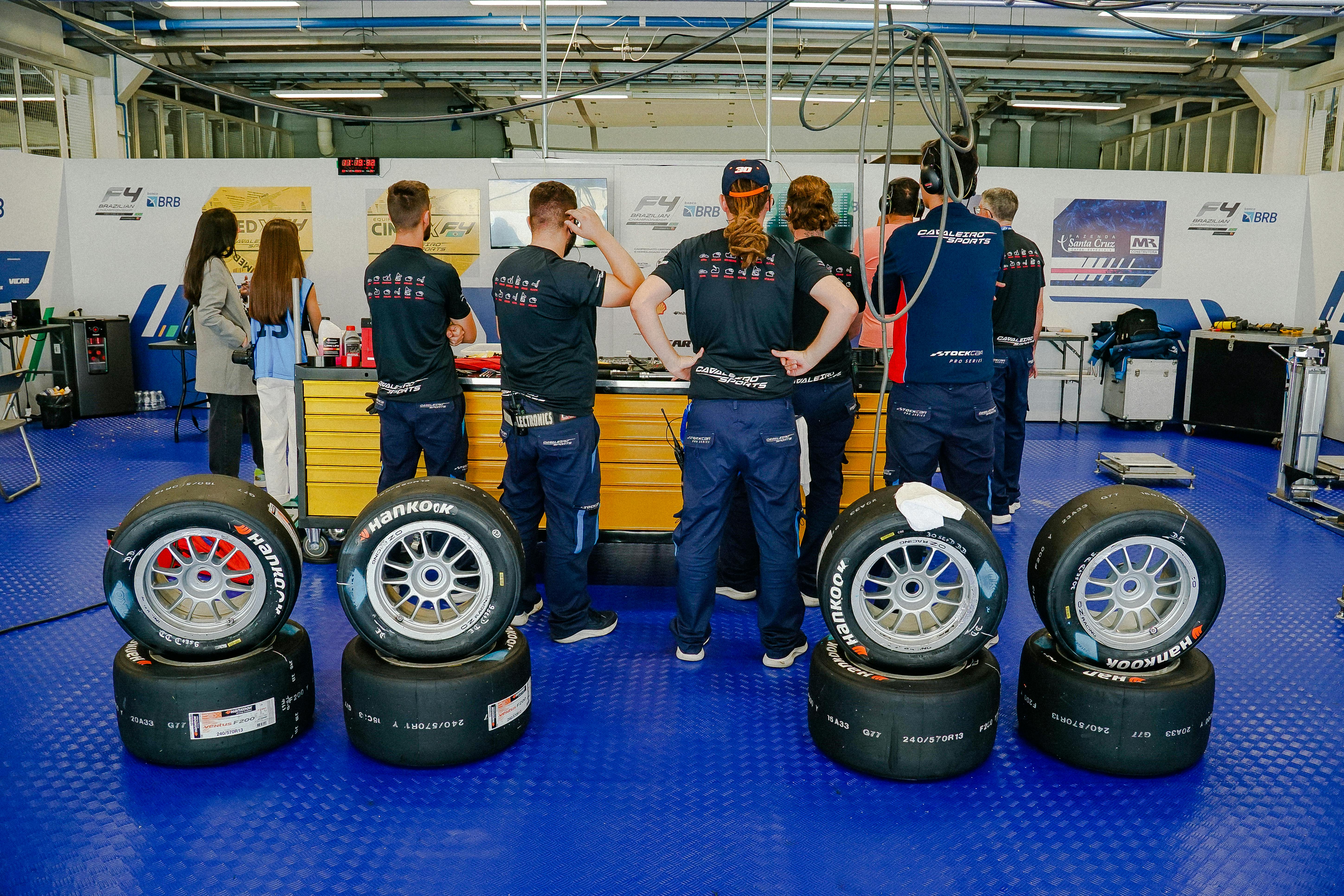 Group of People Standing in a Garage next to a Set of Tires for an F4 ...