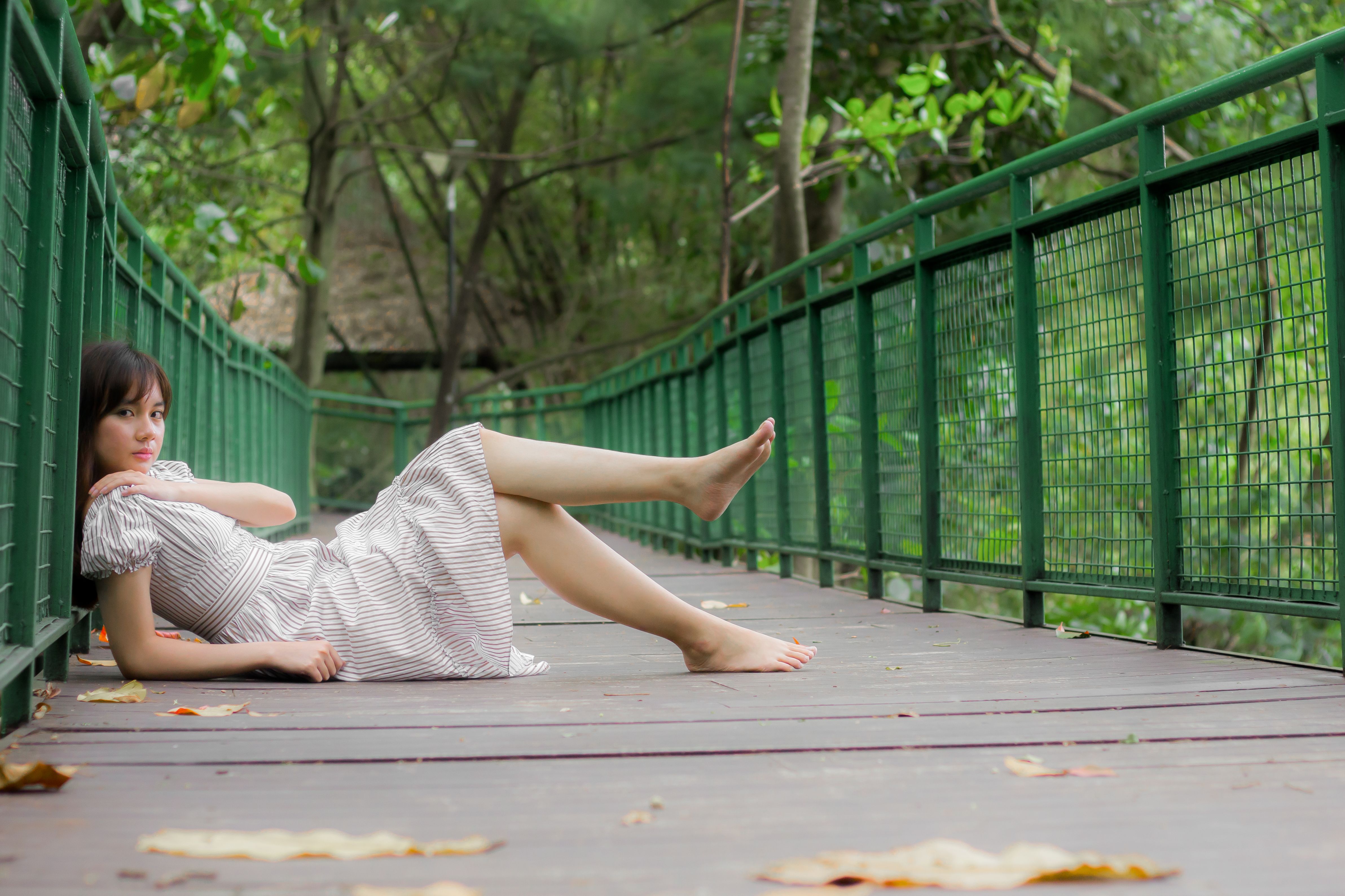 A woman laying on a bridge in the woods · Free Stock Photo