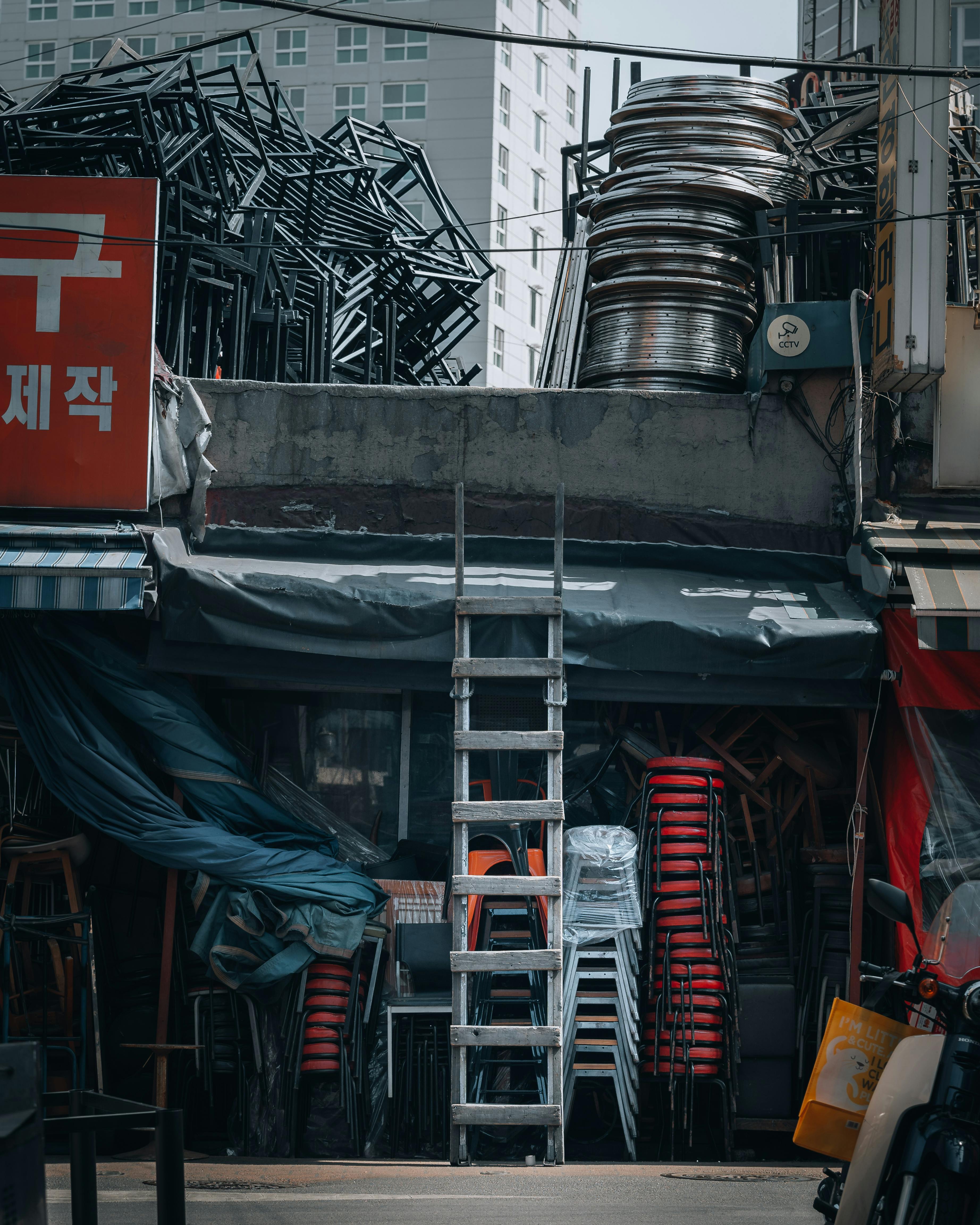 Ladder in Front of a Building Filled with Stacks of Chairs and Stools ...