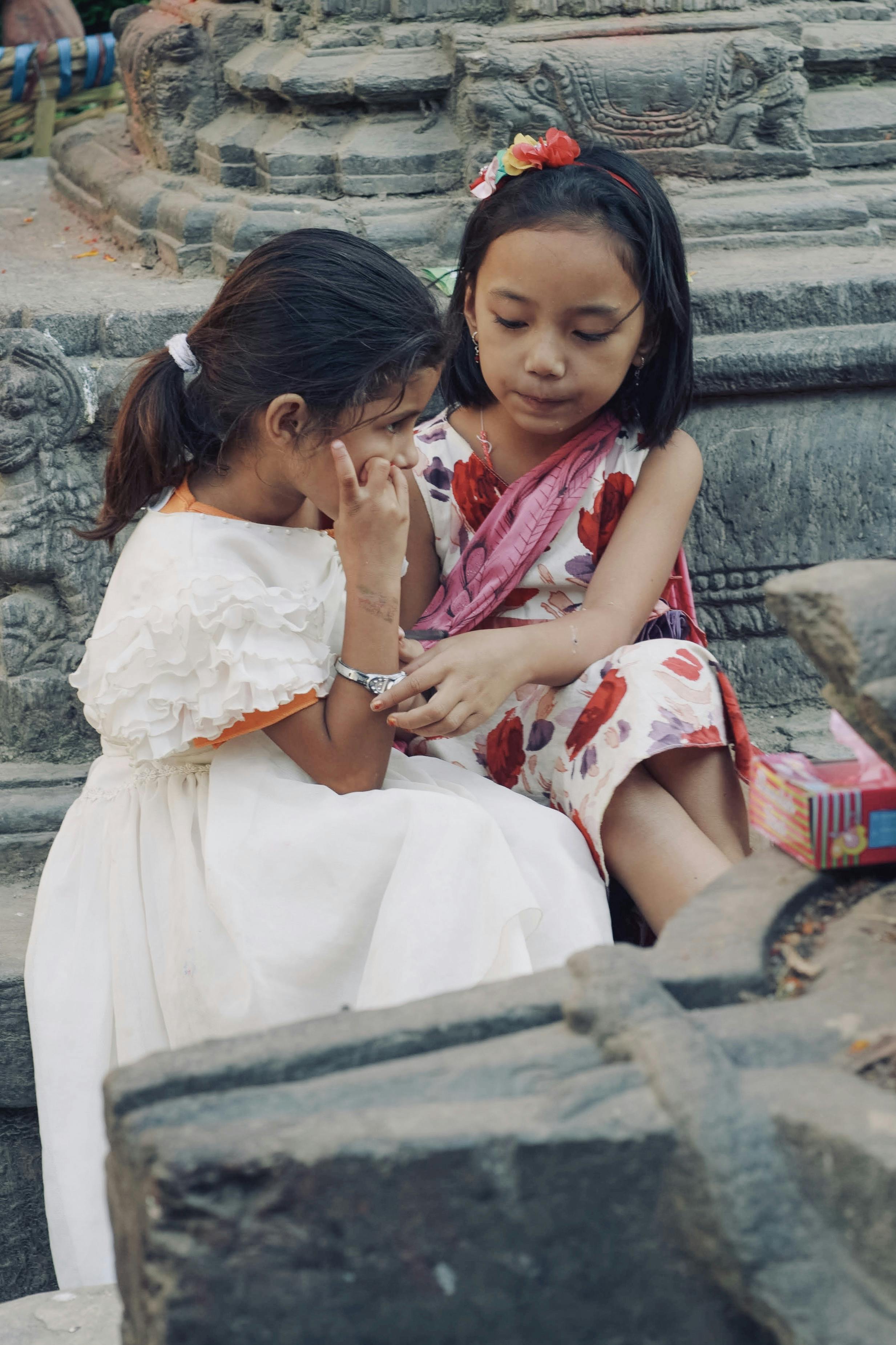 Little Girls Sitting at the Foot of a Stone Statue · Free Stock Photo