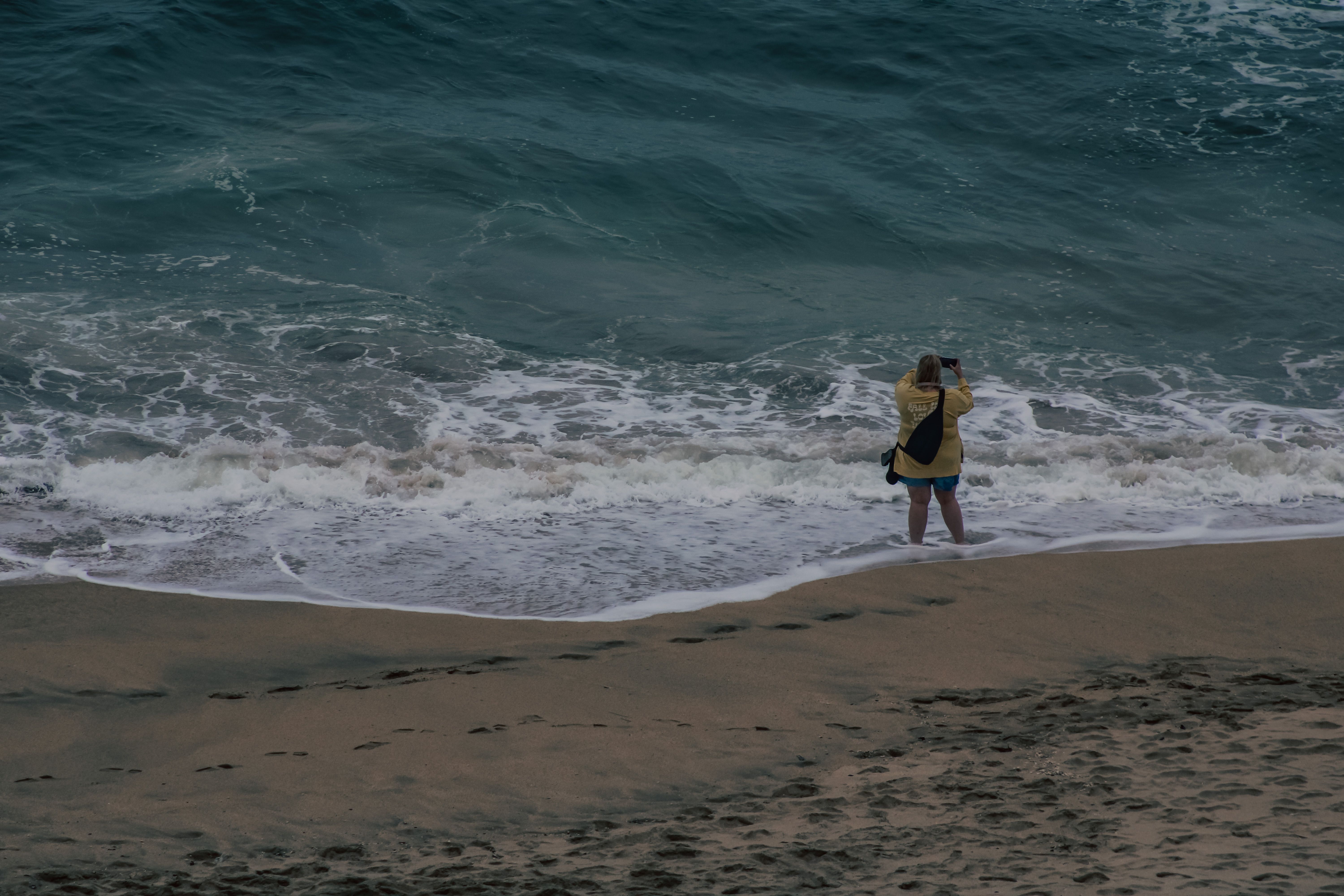 High Angle View of a Woman Standing Ankles Deep in the Sea and Taking a ...