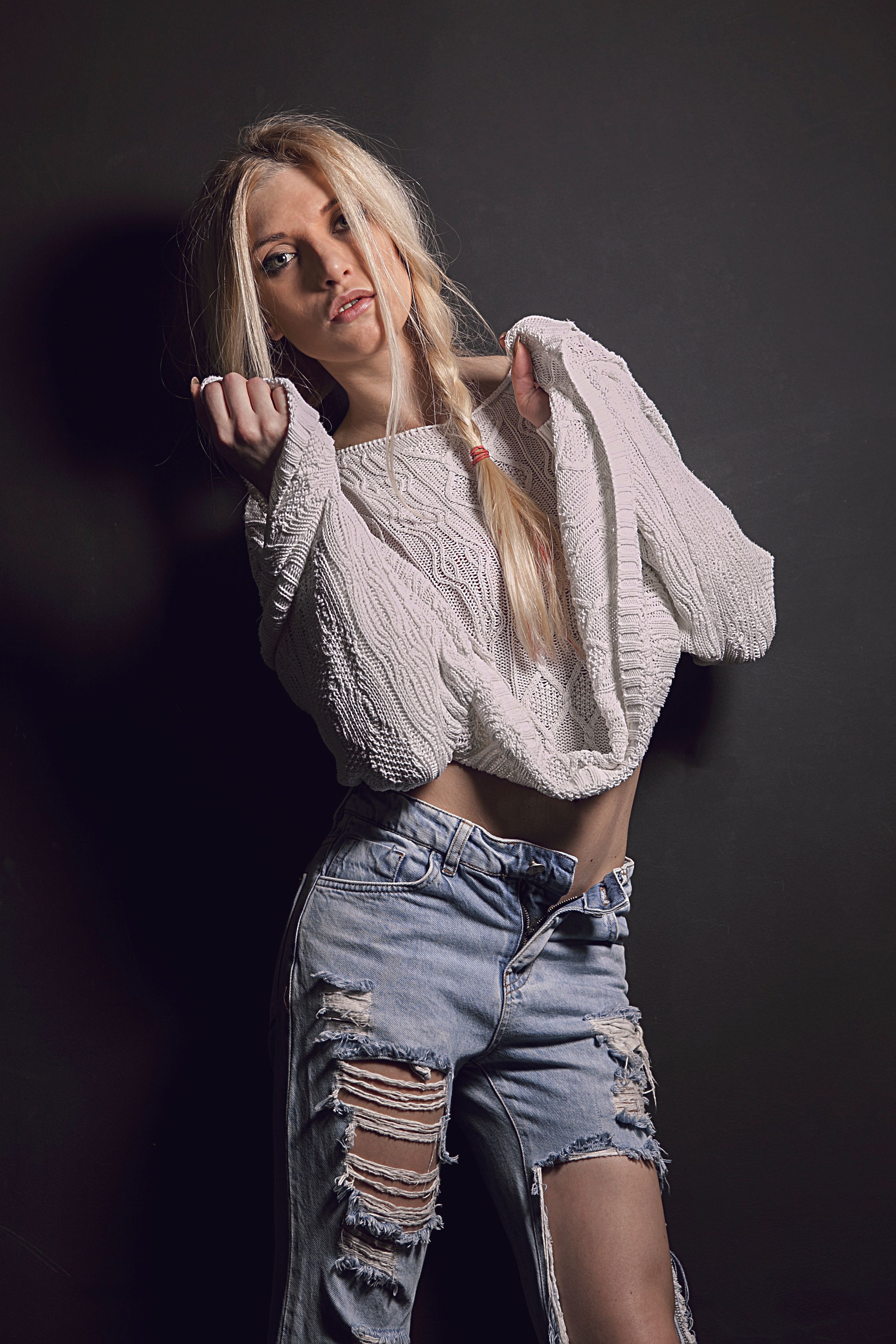 Studio Shot of a Young Woman Wearing Ripped Jeans · Free Stock Photo