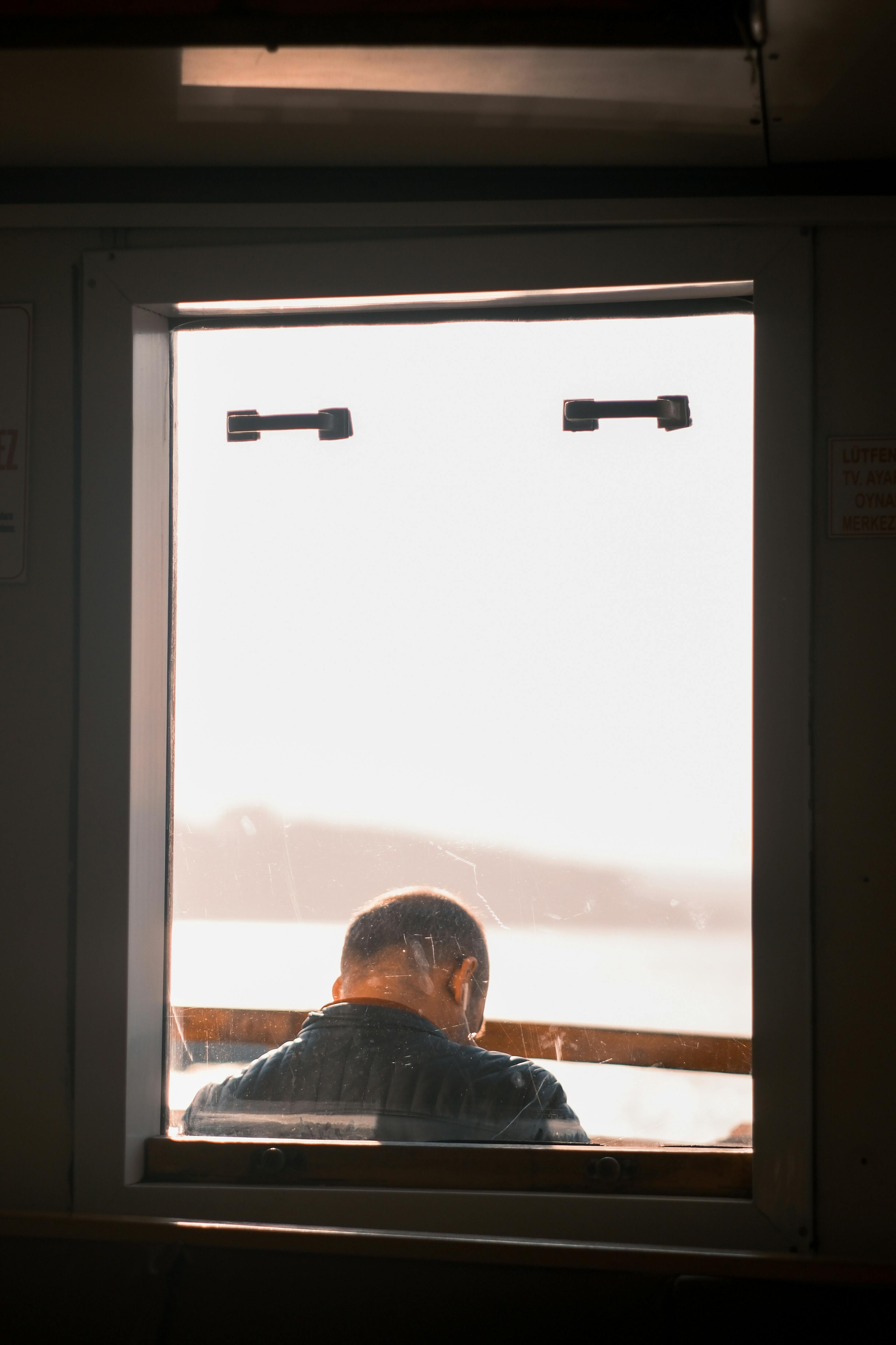 Back View of a Man Sitting on a Boat Photographed from behind a Window ...