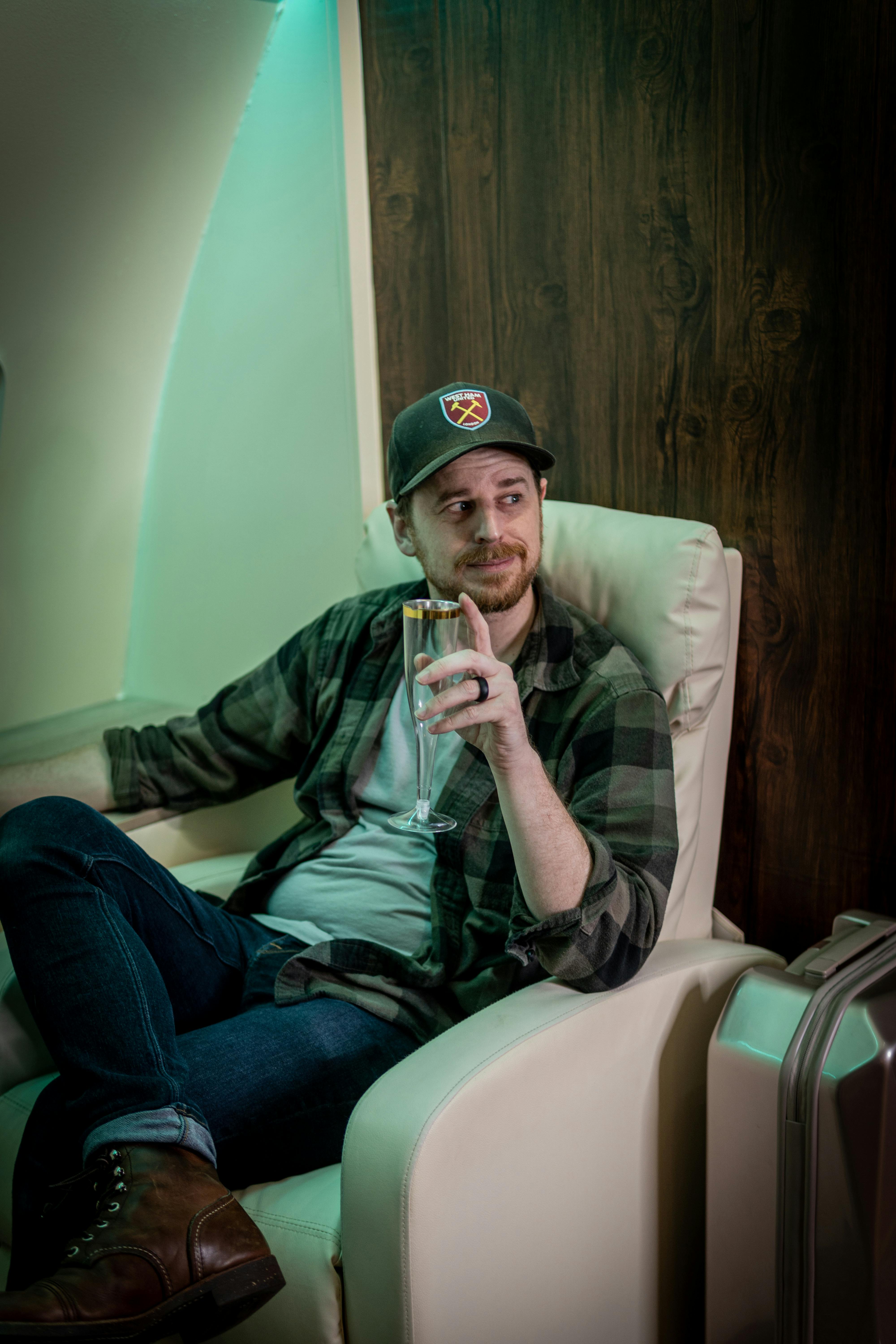 Man in West Ham Cap Sitting and Drinking · Free Stock Photo