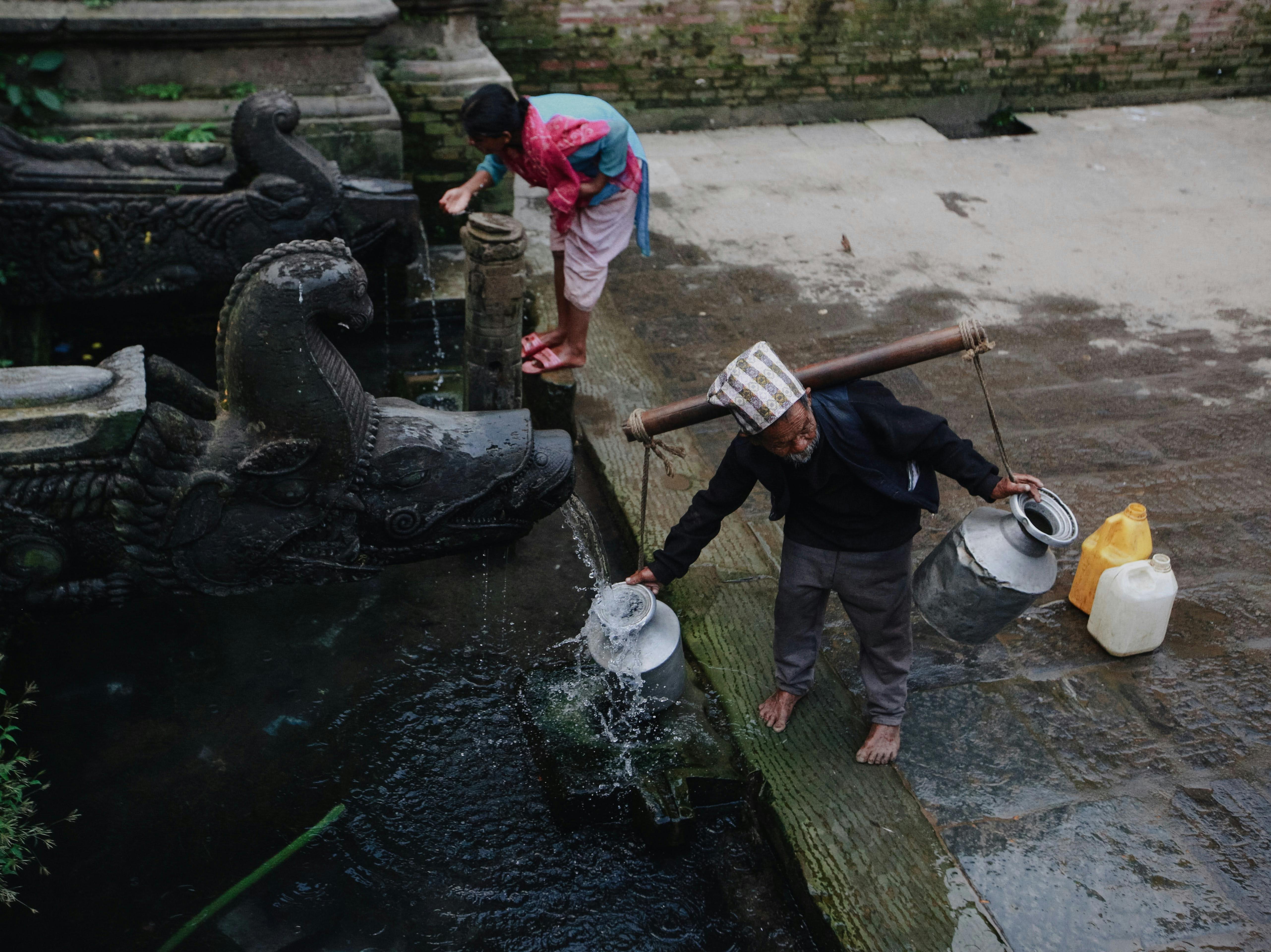 Elderly Man Filling Buckets with Water · Free Stock Photo