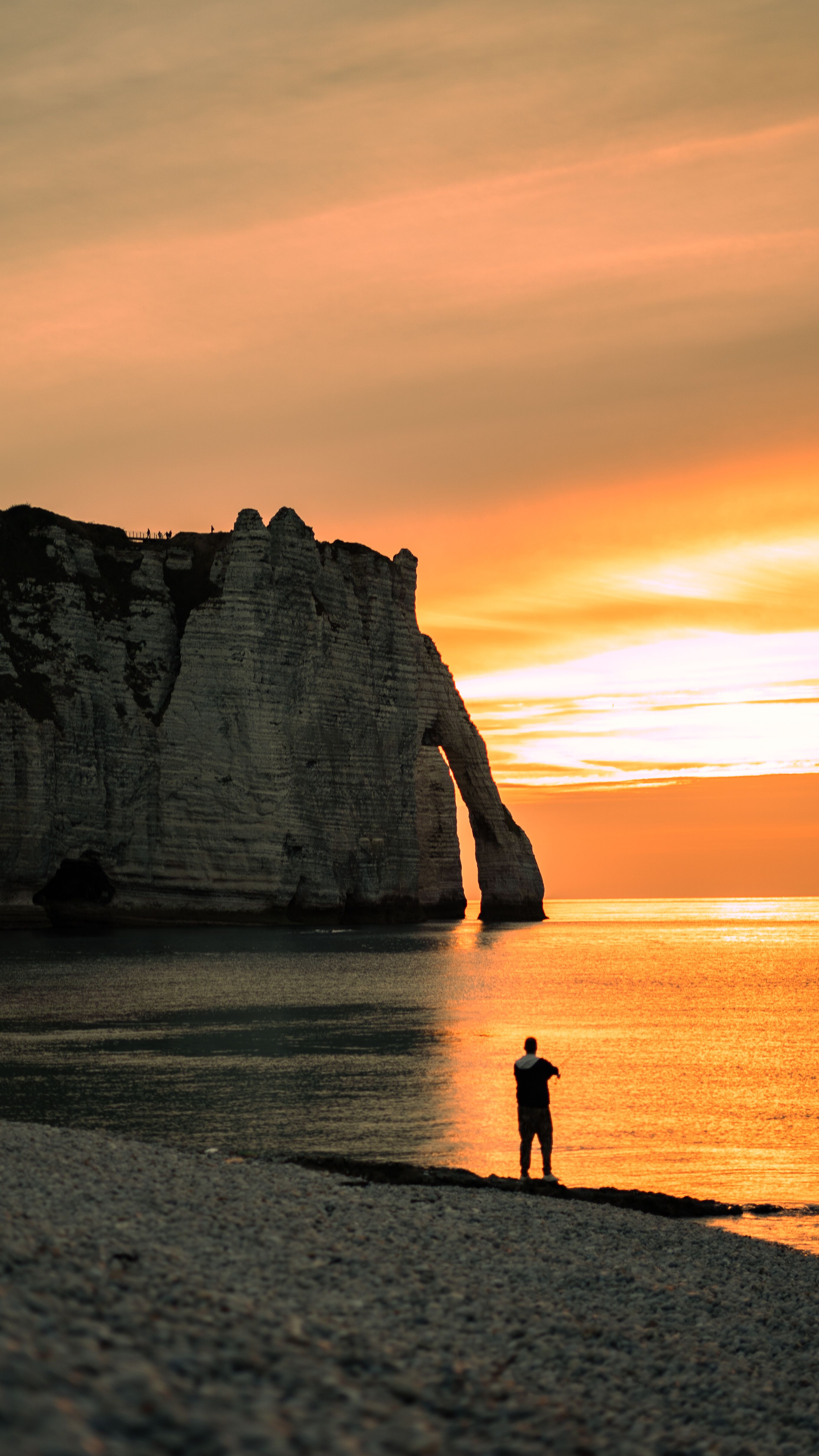 Man on Sea Shore with Cliff behind at Sunset · Free Stock Photo