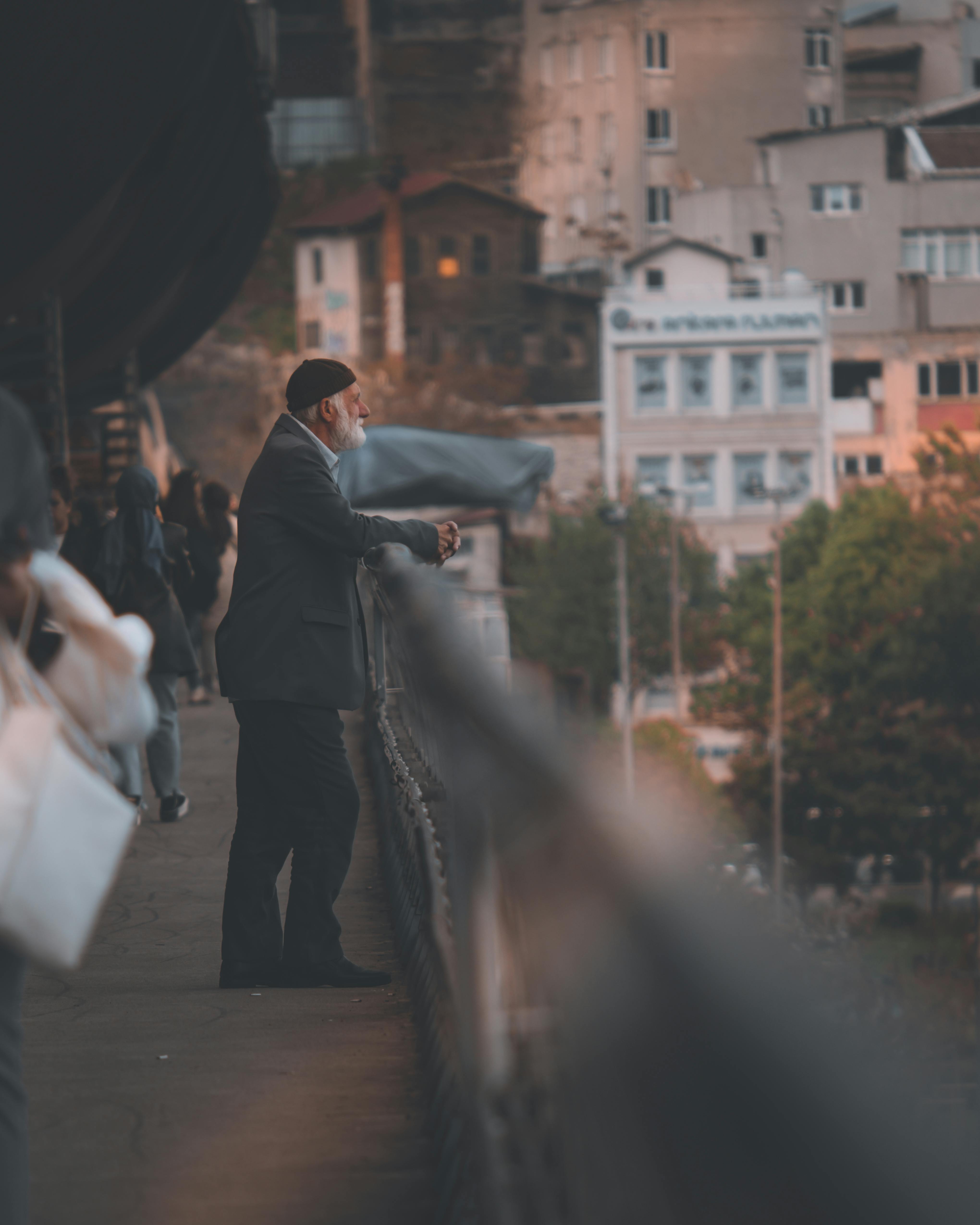 Elderly Man Standing by Railing on Footbridge in City · Free Stock Photo
