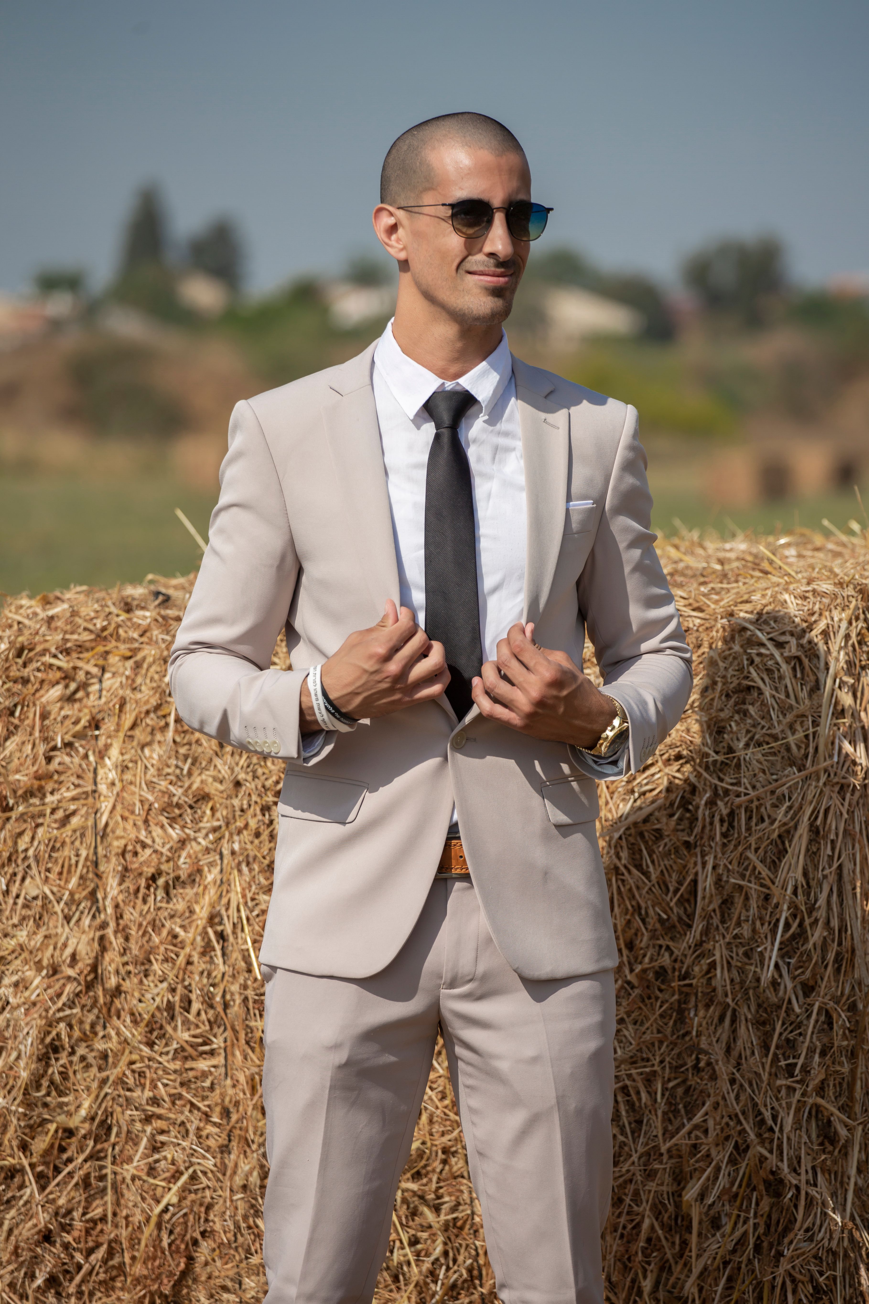 A man in a suit and tie standing in front of hay bales · Free Stock Photo