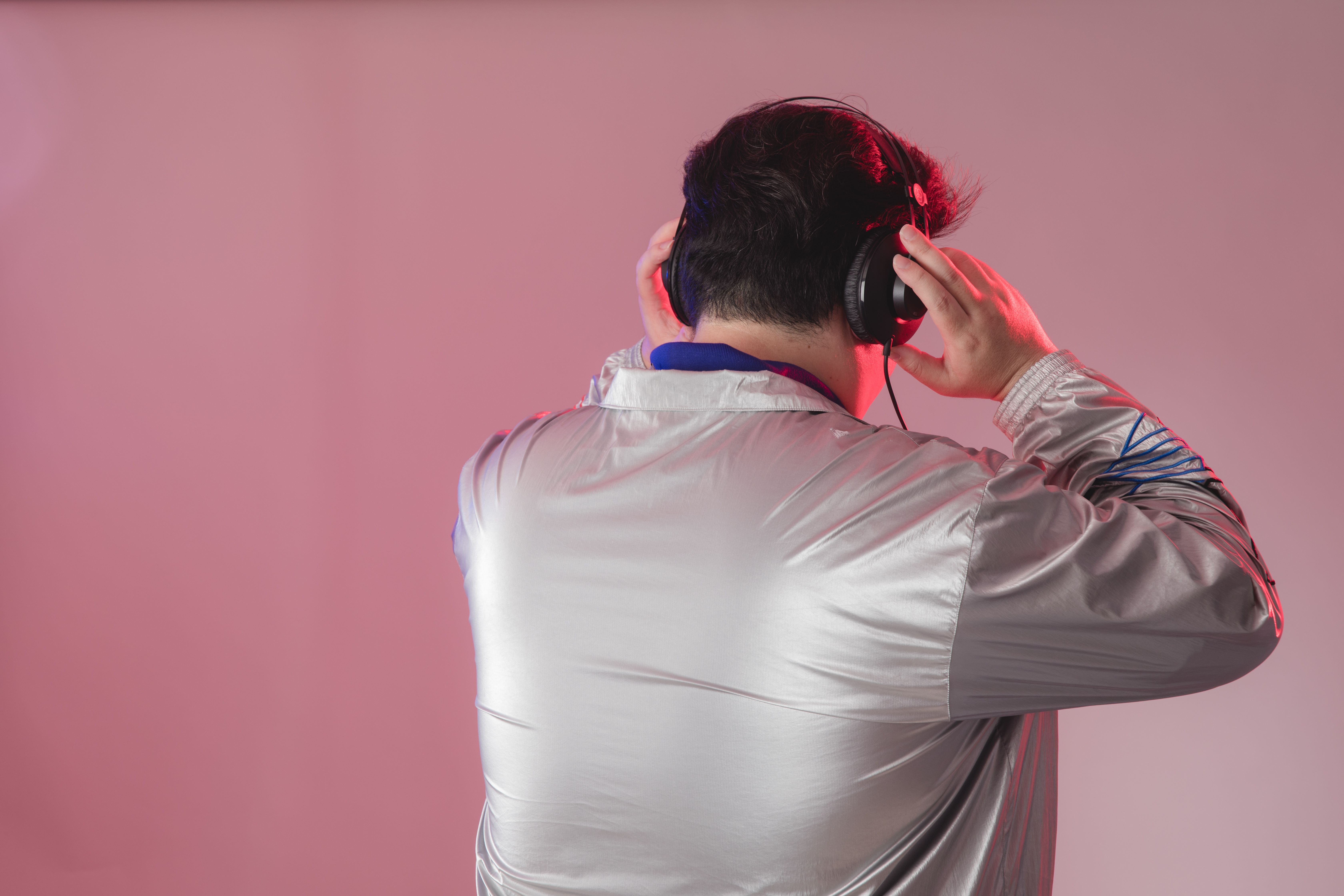Back View of a Man in a Silver Jacket Wearing Headphones · Free Stock Photo