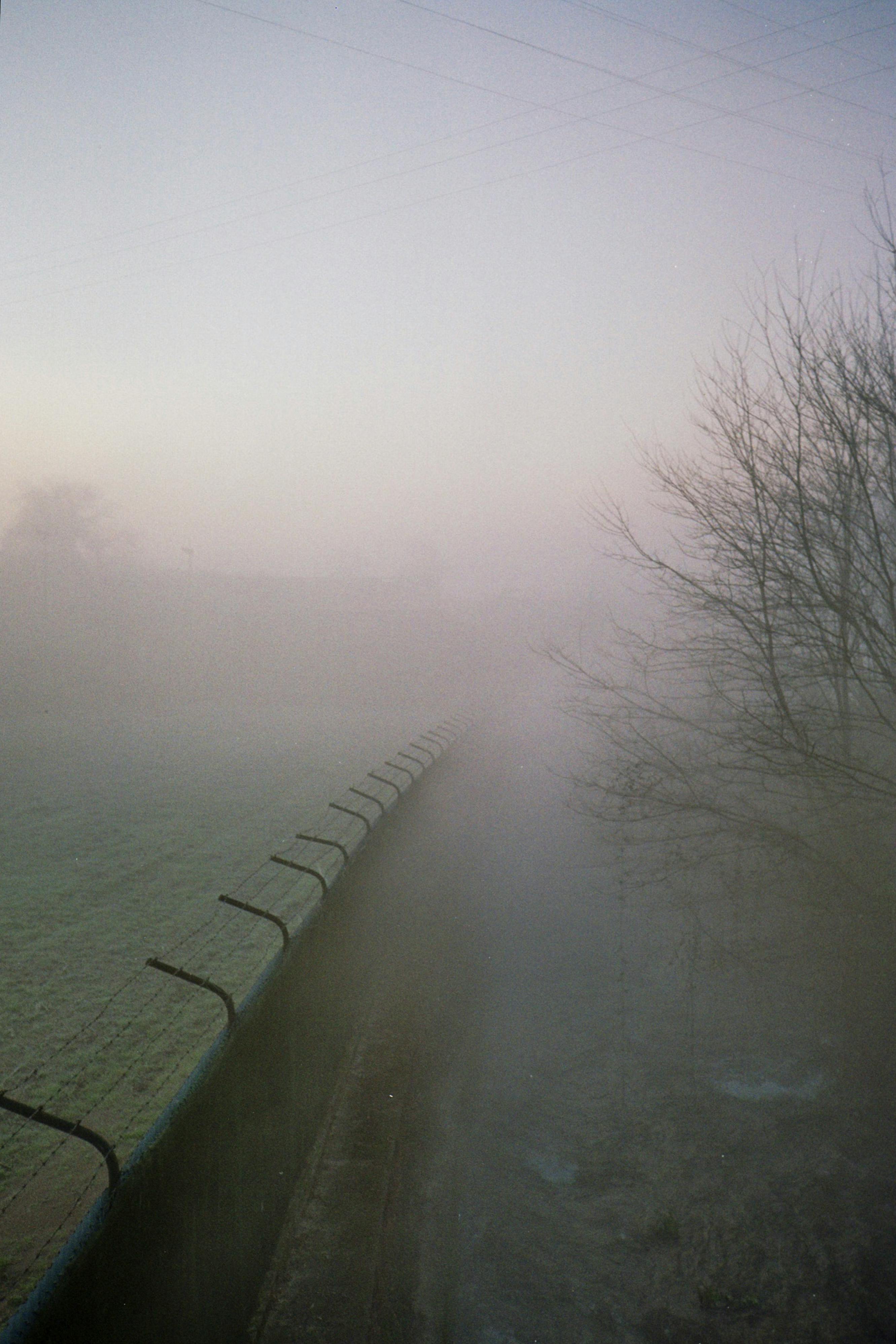 A Field with a Fence on a Foggy Day · Free Stock Photo