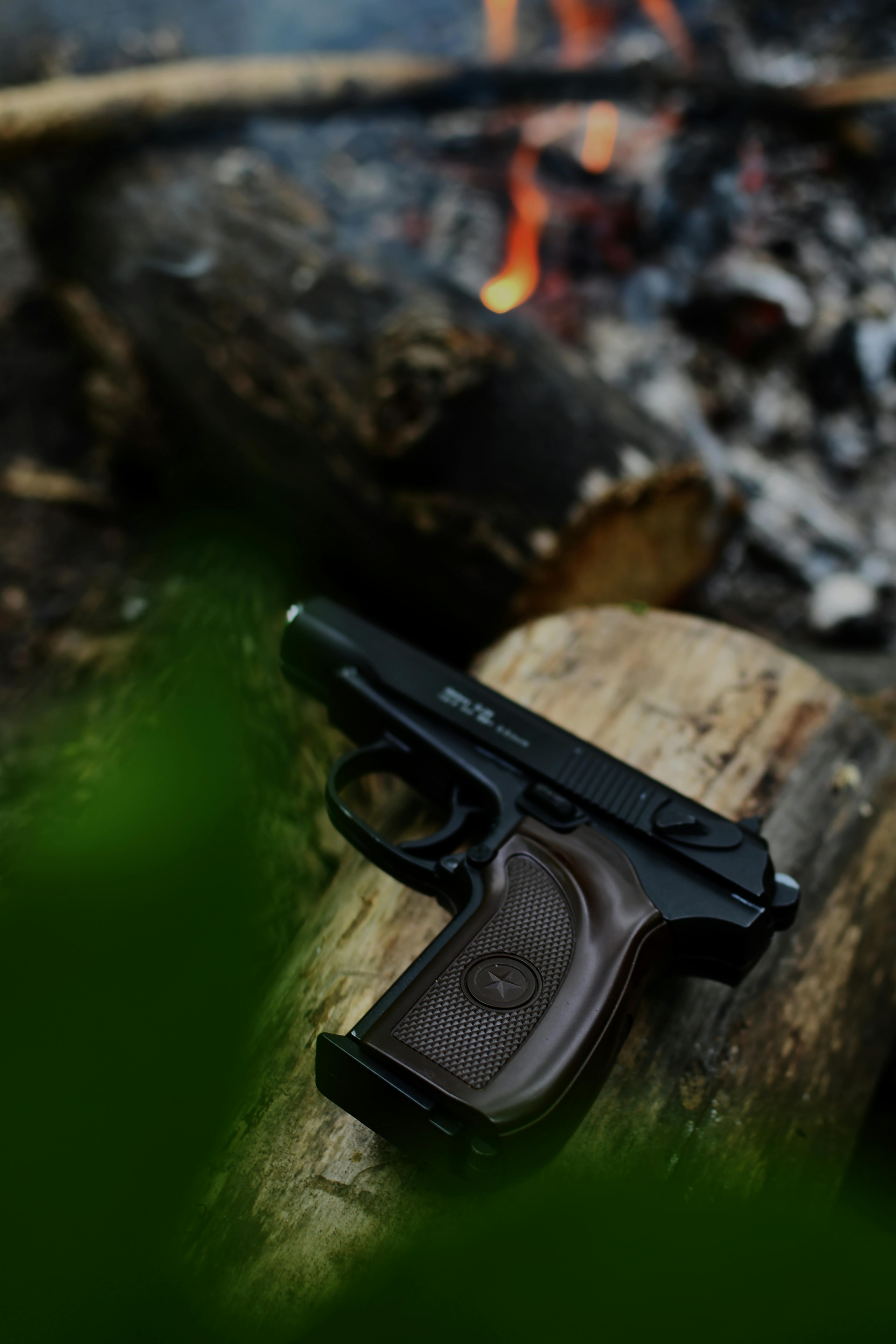 Makarov Pistol Lying on Tree Log next to Campfire · Free Stock Photo