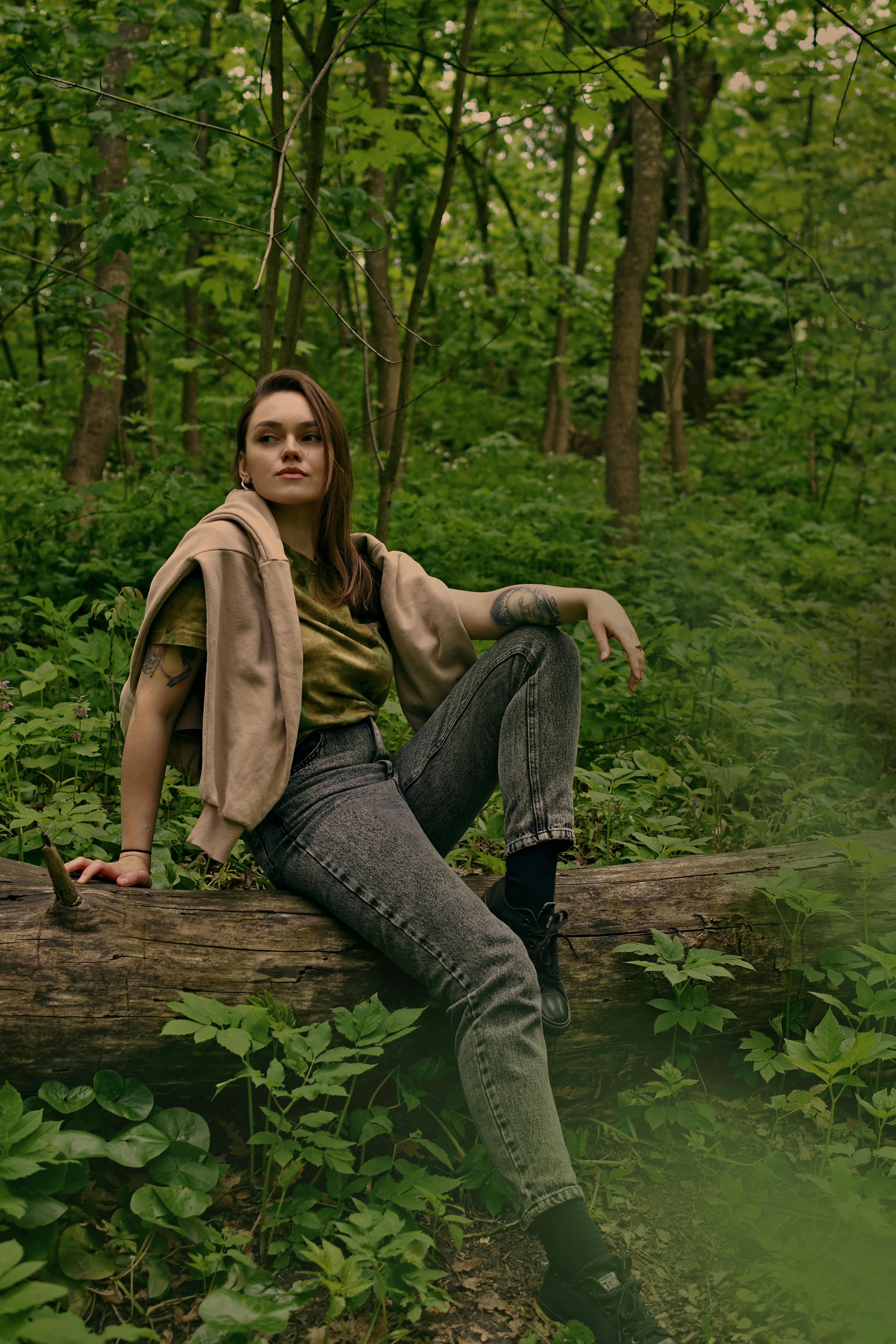Woman Sitting on Fallen Tree in Green Forest · Free Stock Photo