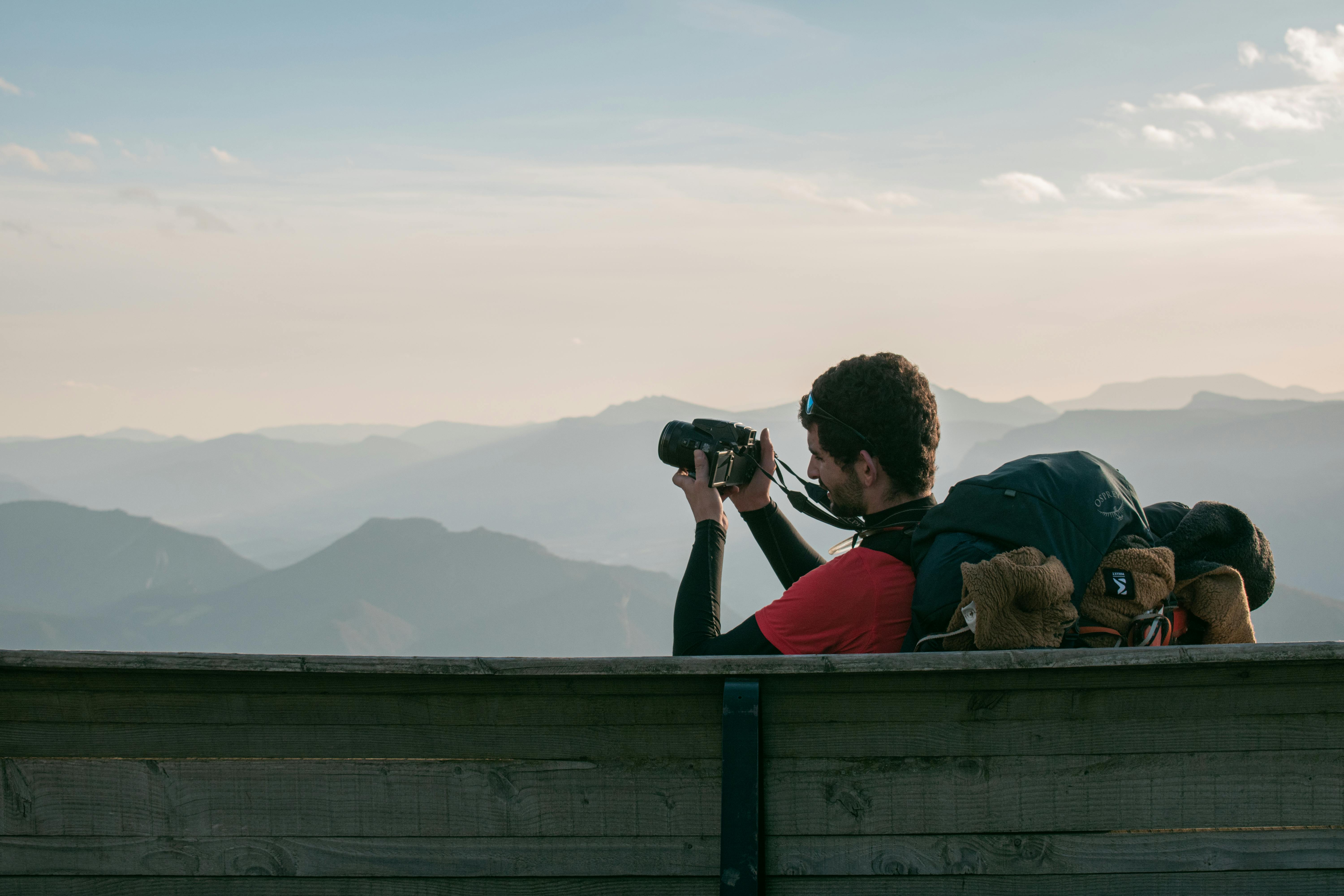 Backpacker with Camera in Mountains · Free Stock Photo