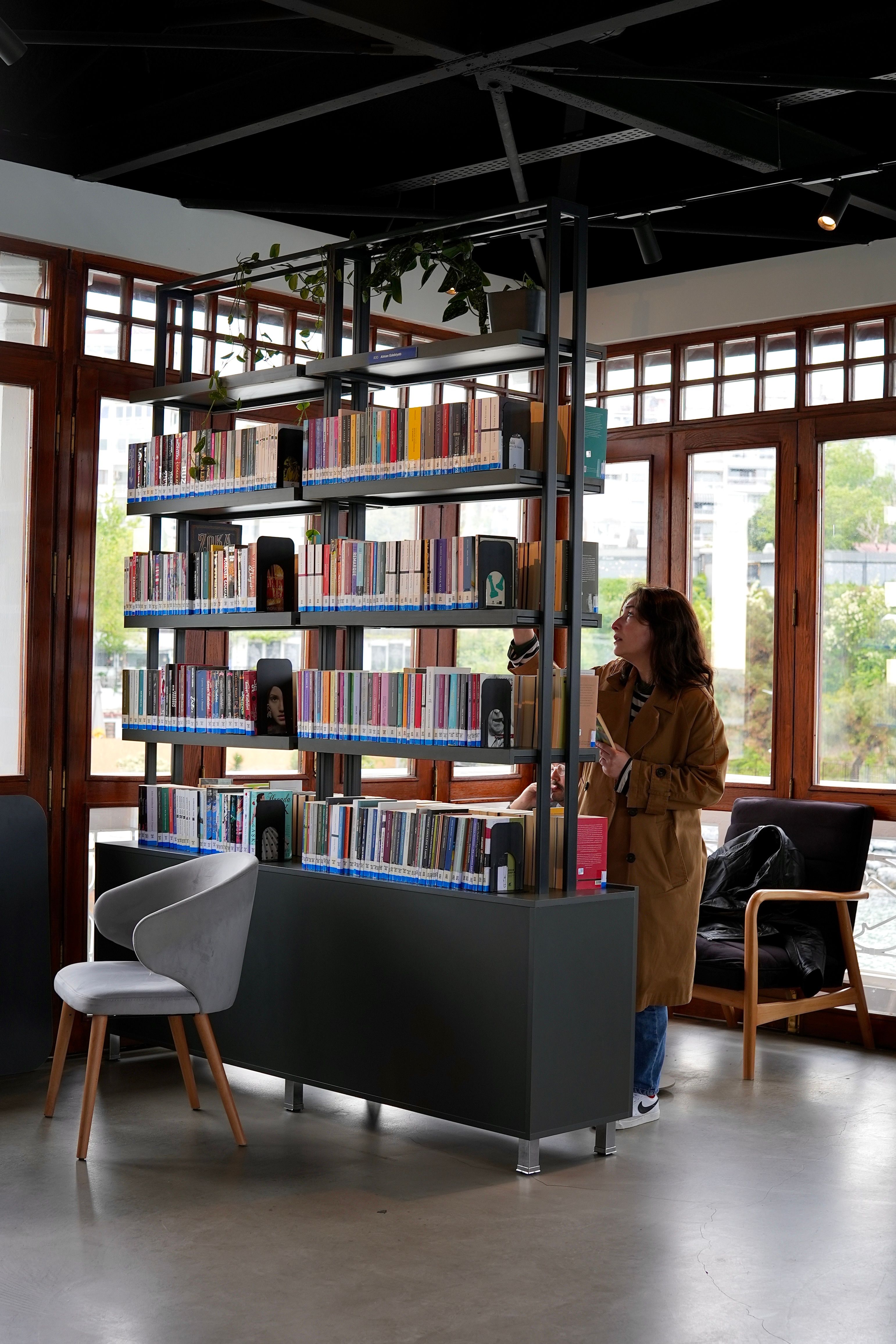 Woman Standing near Books on Shelves in Library · Free Stock Photo