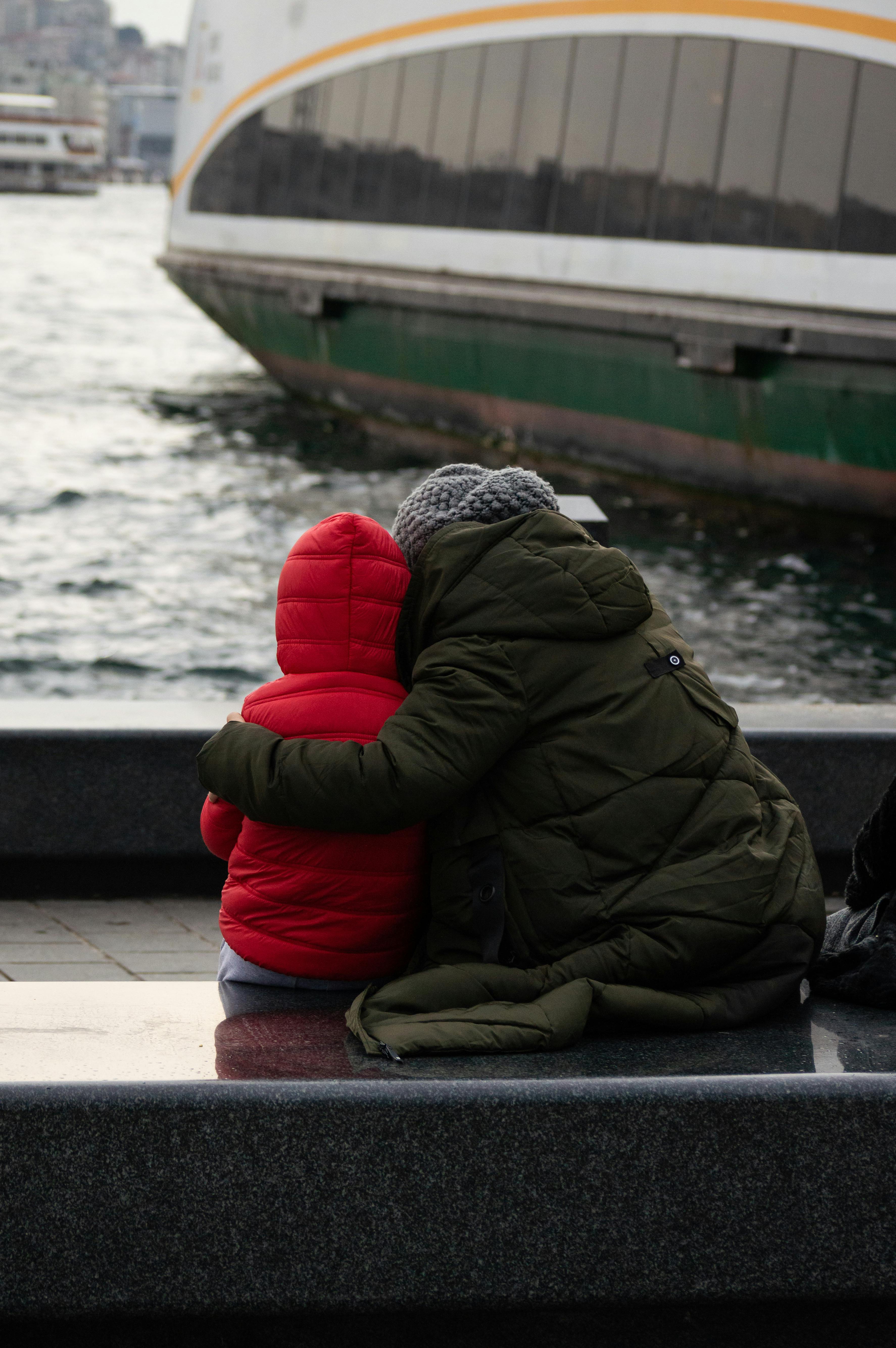 Mother Hugging Child near Water in City · Free Stock Photo