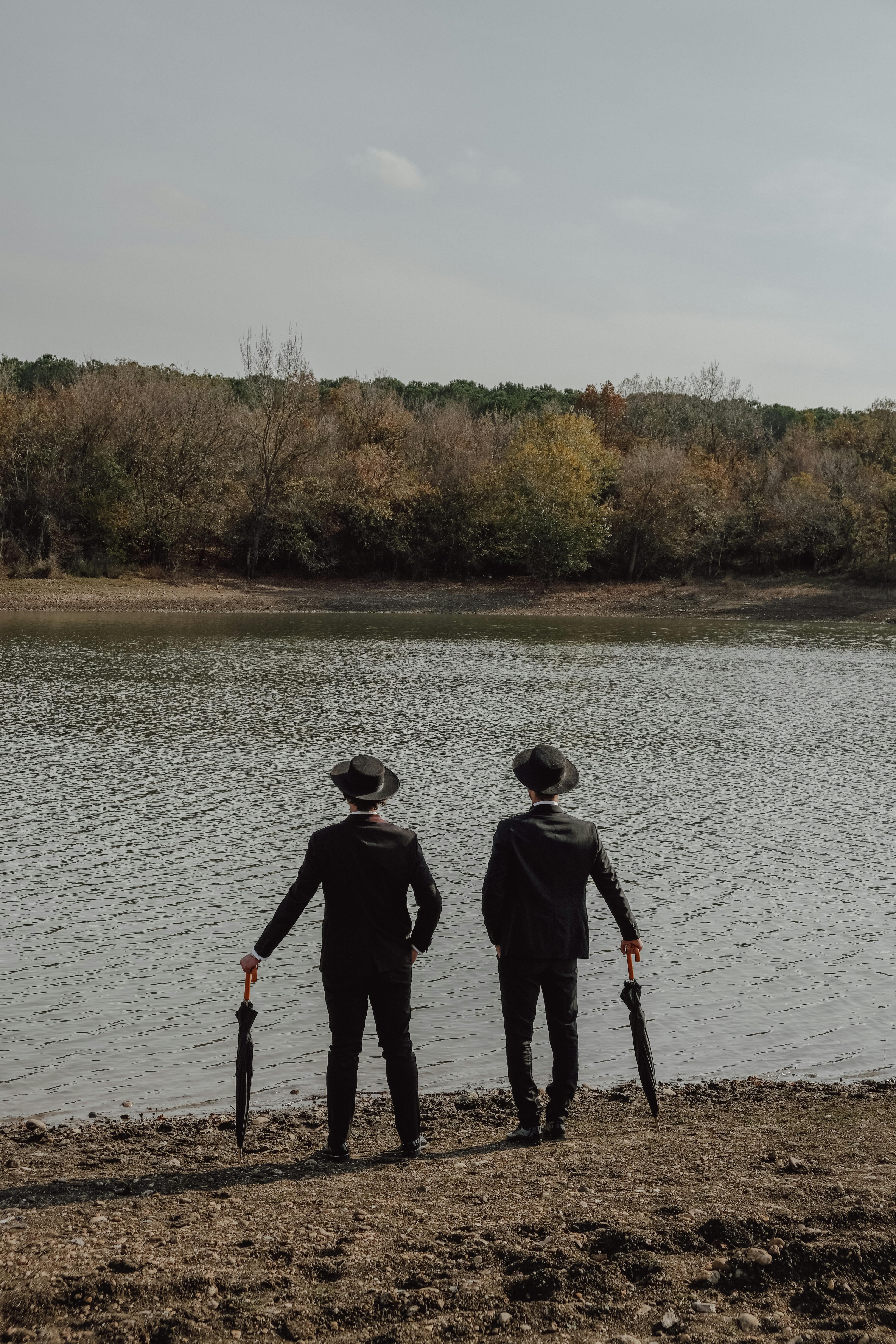 Two Men in Suits Standing on a Riverbank · Free Stock Photo