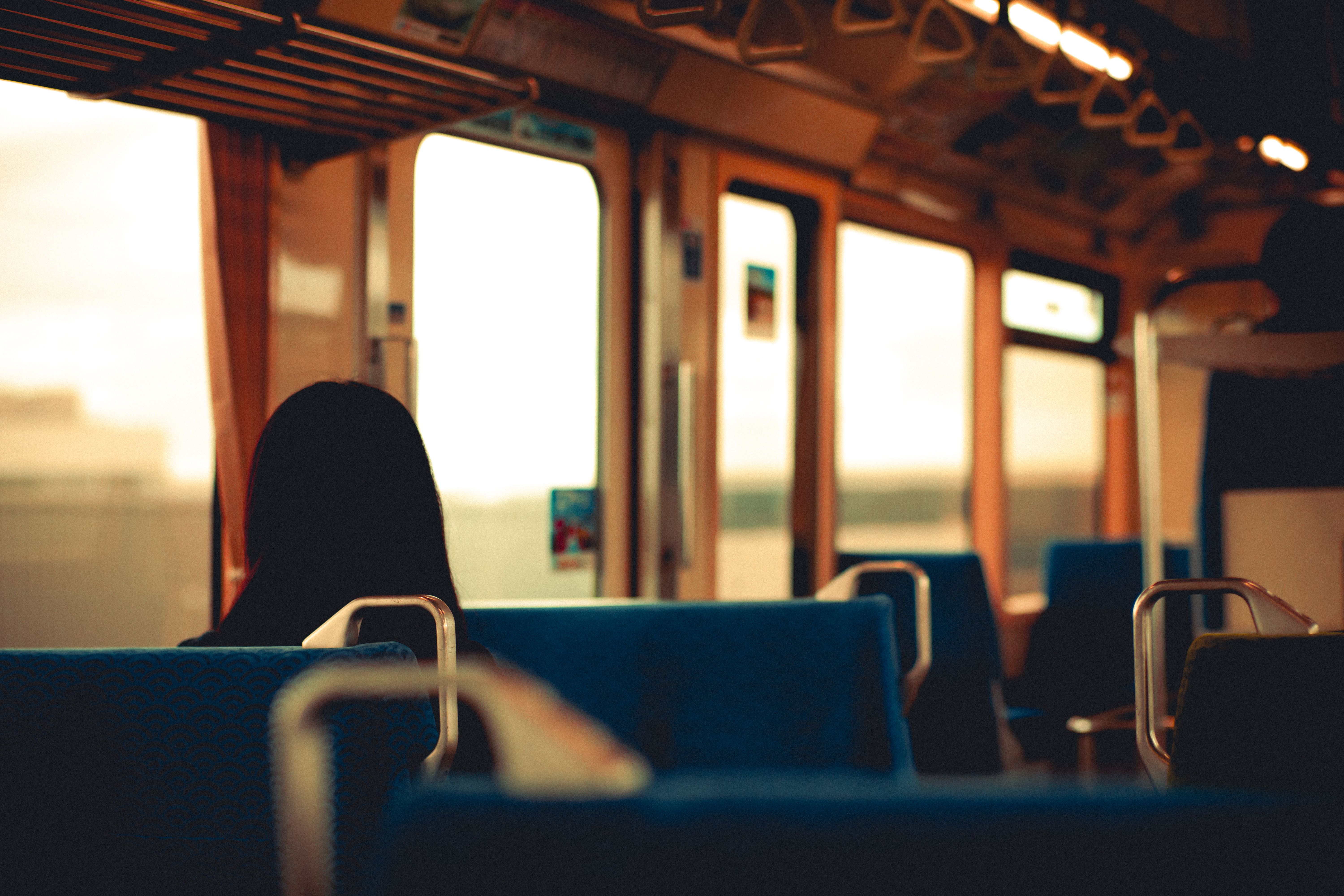 A woman sitting on a train with her back to the camera · Free Stock Photo