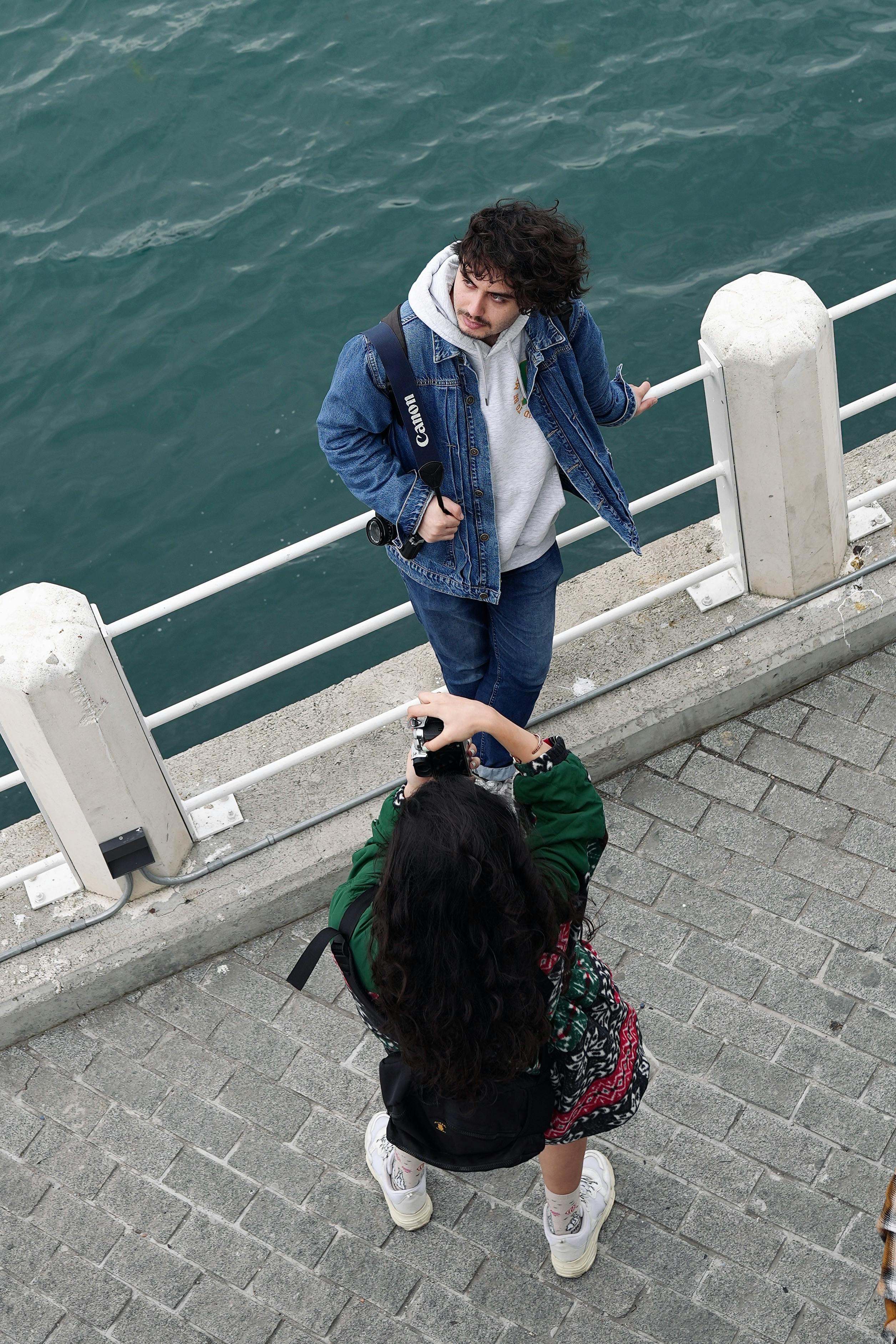 Woman Photographing Man in Jeans in Seaside · Free Stock Photo