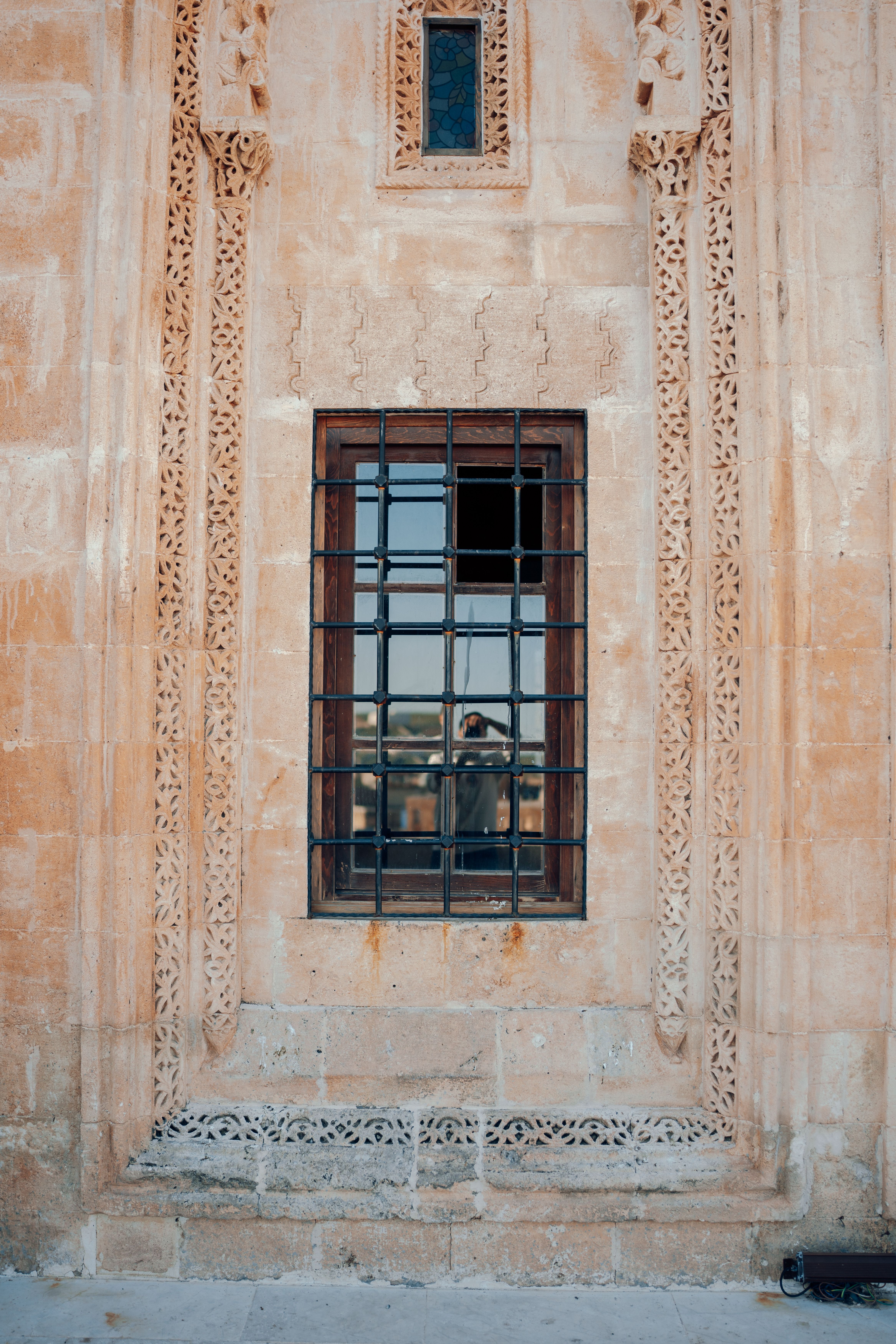 Barred Window in Sandstone Wall with Photographer Reflection in the ...