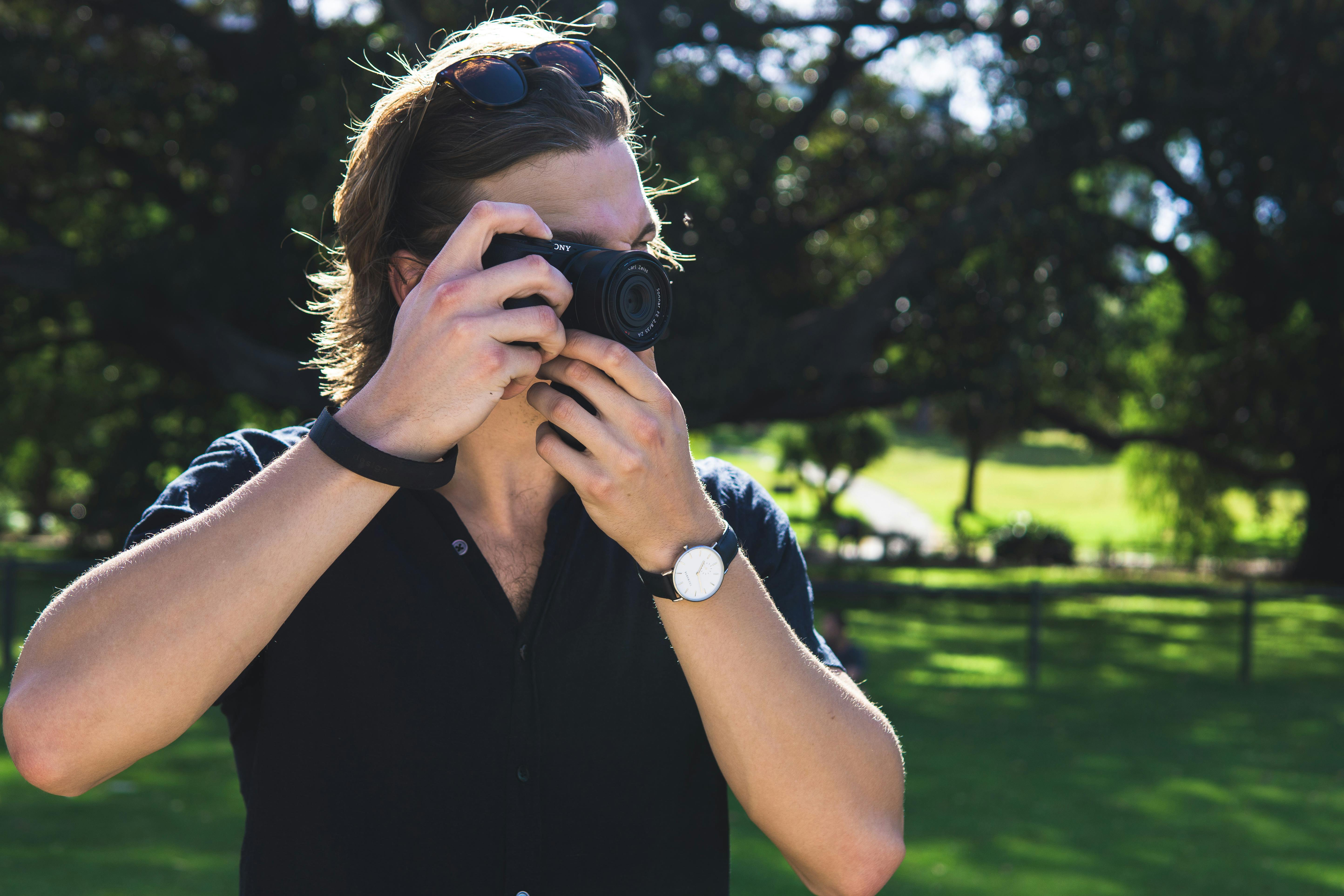 Standing Man Holding Camera and Taking Photo · Free Stock Photo