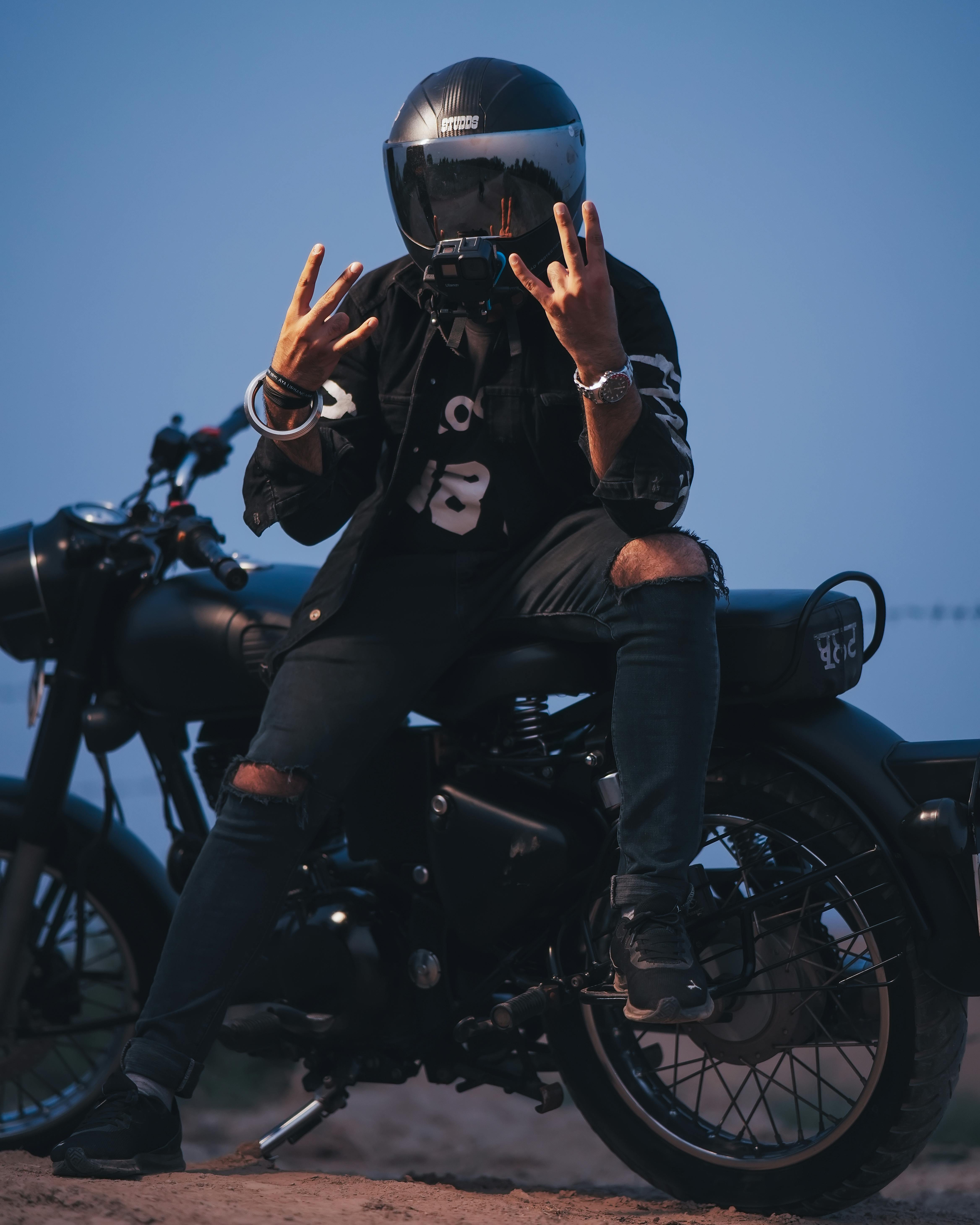 A man sitting on a motorcycle with his hands up · Free Stock Photo