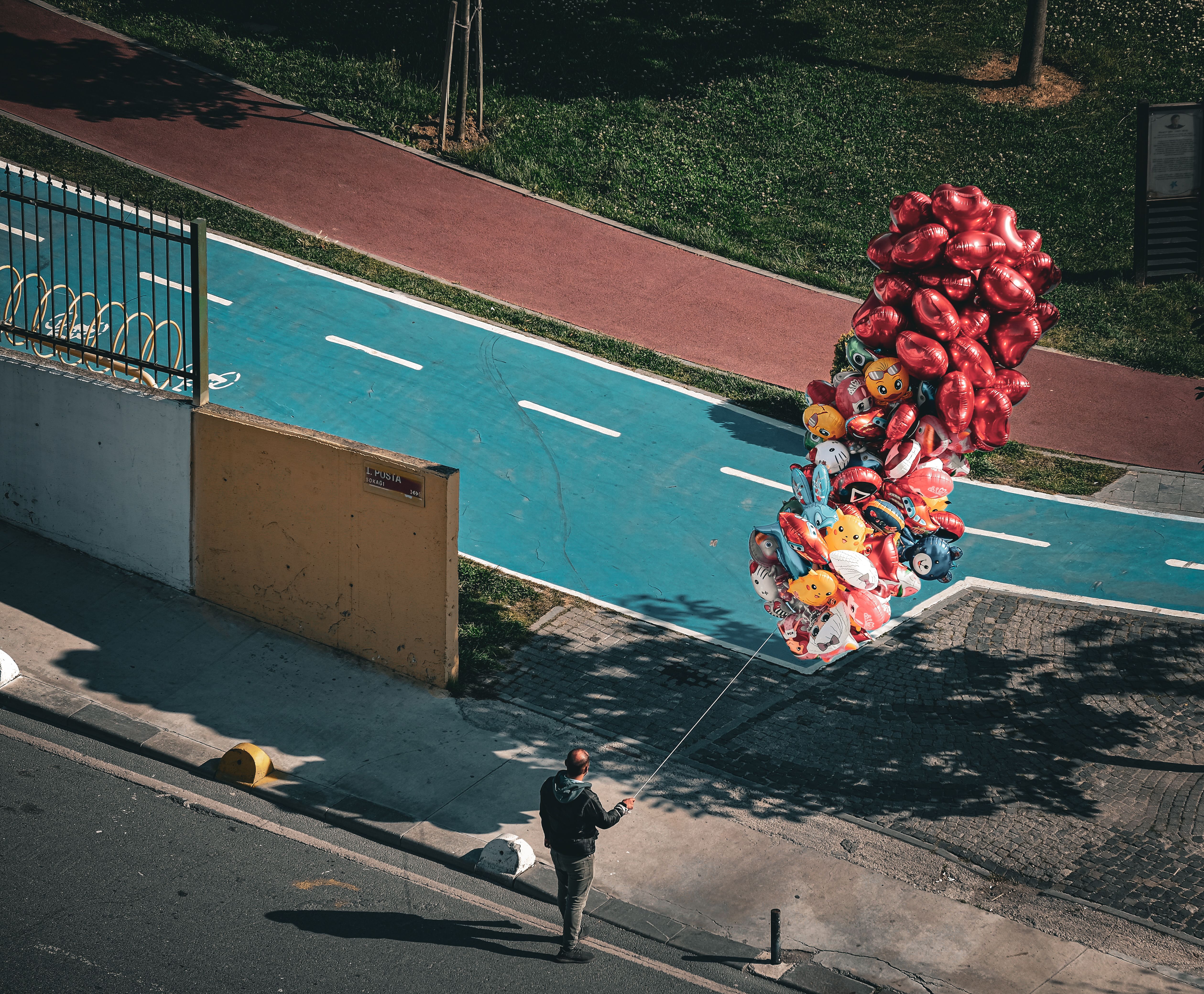 Man Holding Balloons by the Street · Free Stock Photo