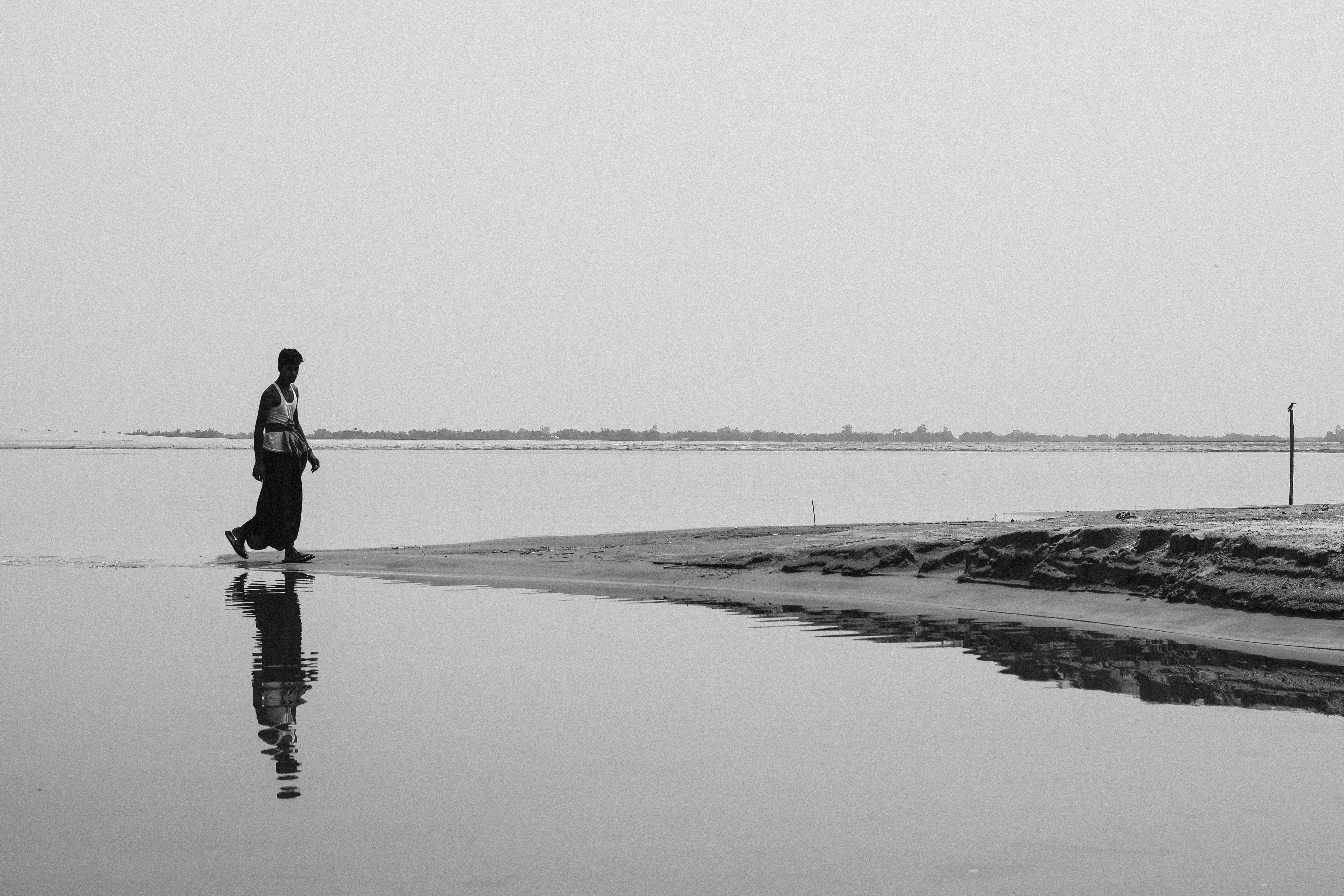 Reflection of an alone man walking on the river bank · Free Stock Photo