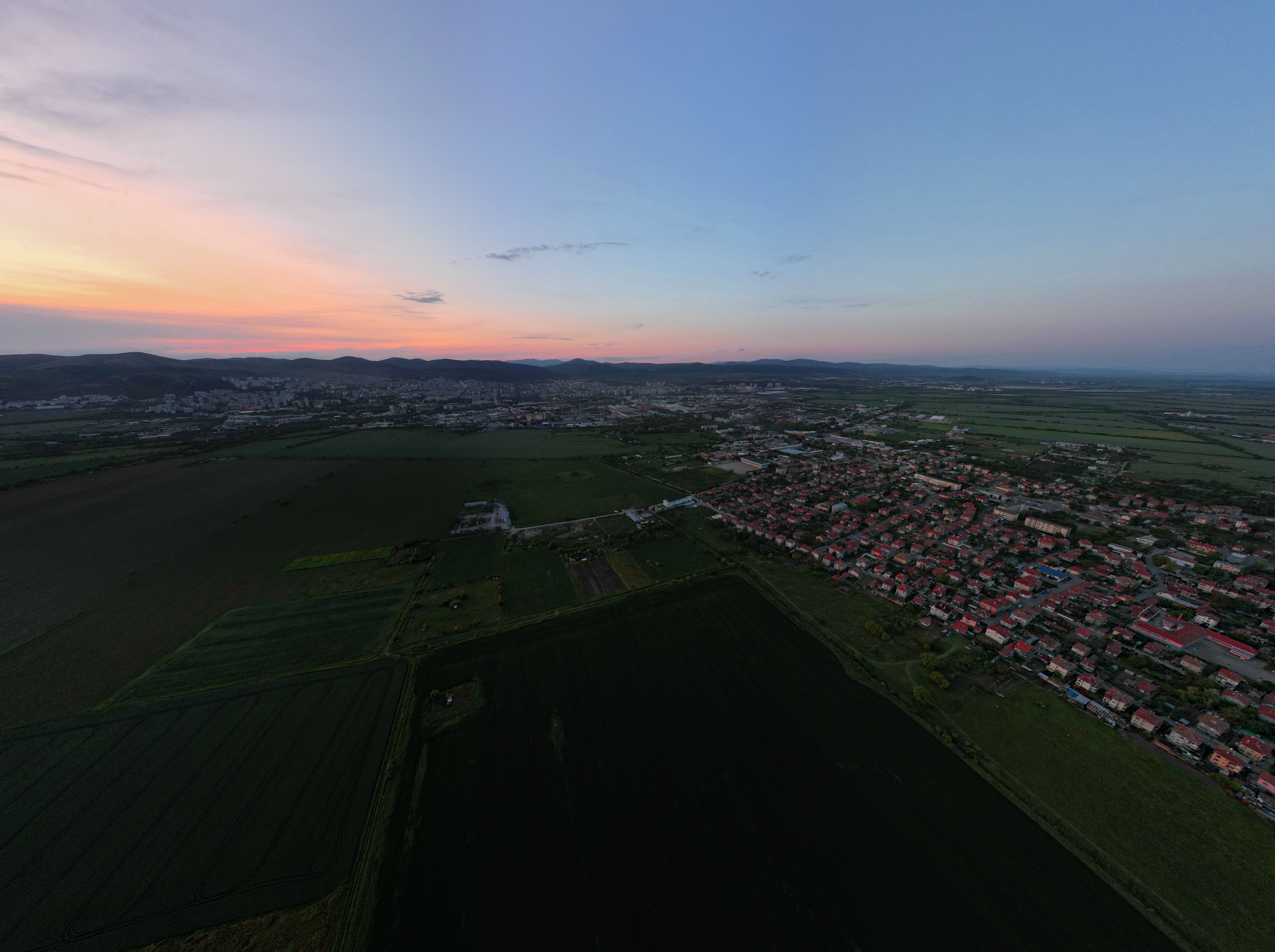 A view of a small town and farmland at sunset · Free Stock Photo