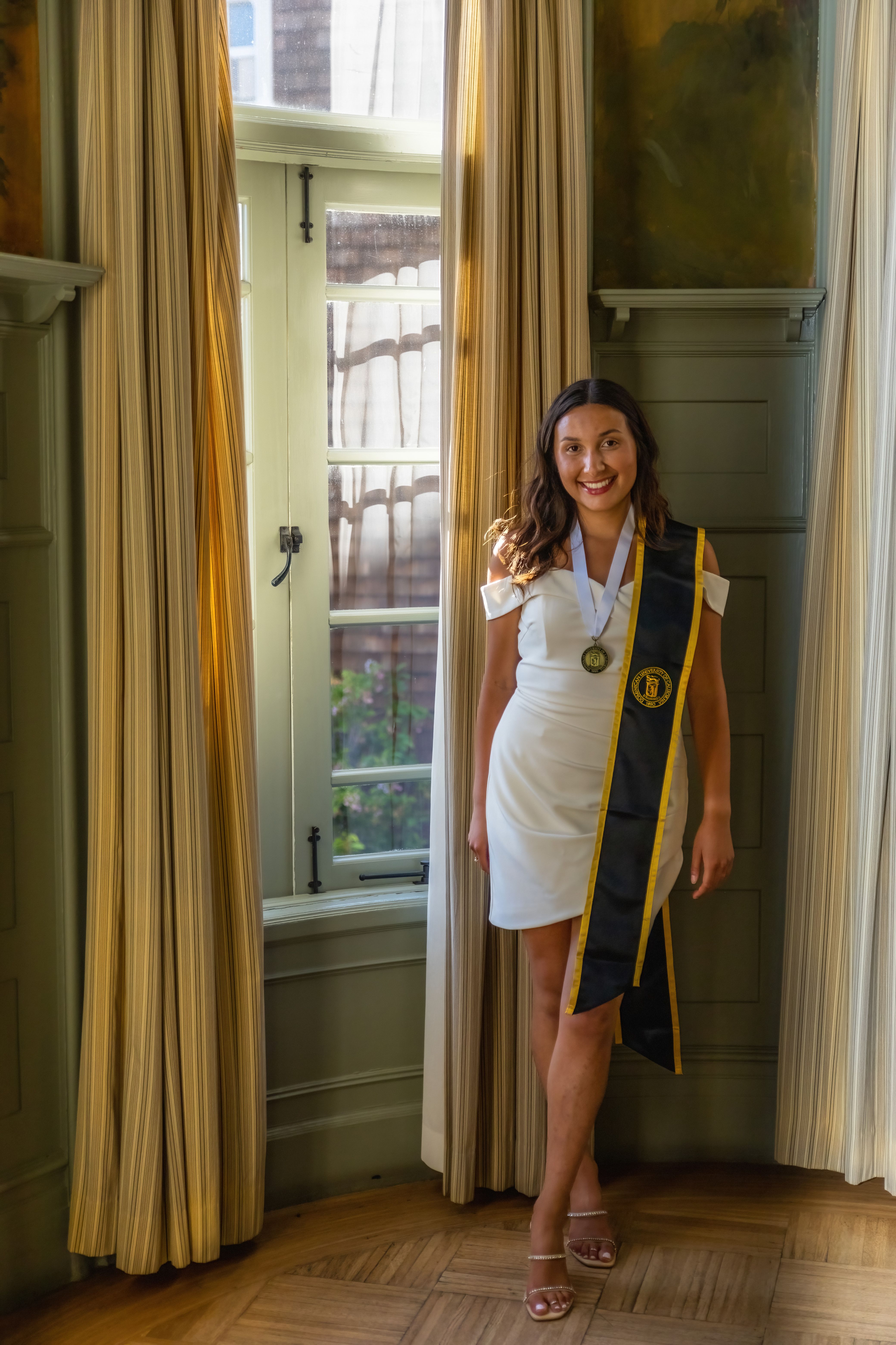 Woman Wearing Medal and Graduation Sash Standing under Apartment Window ...