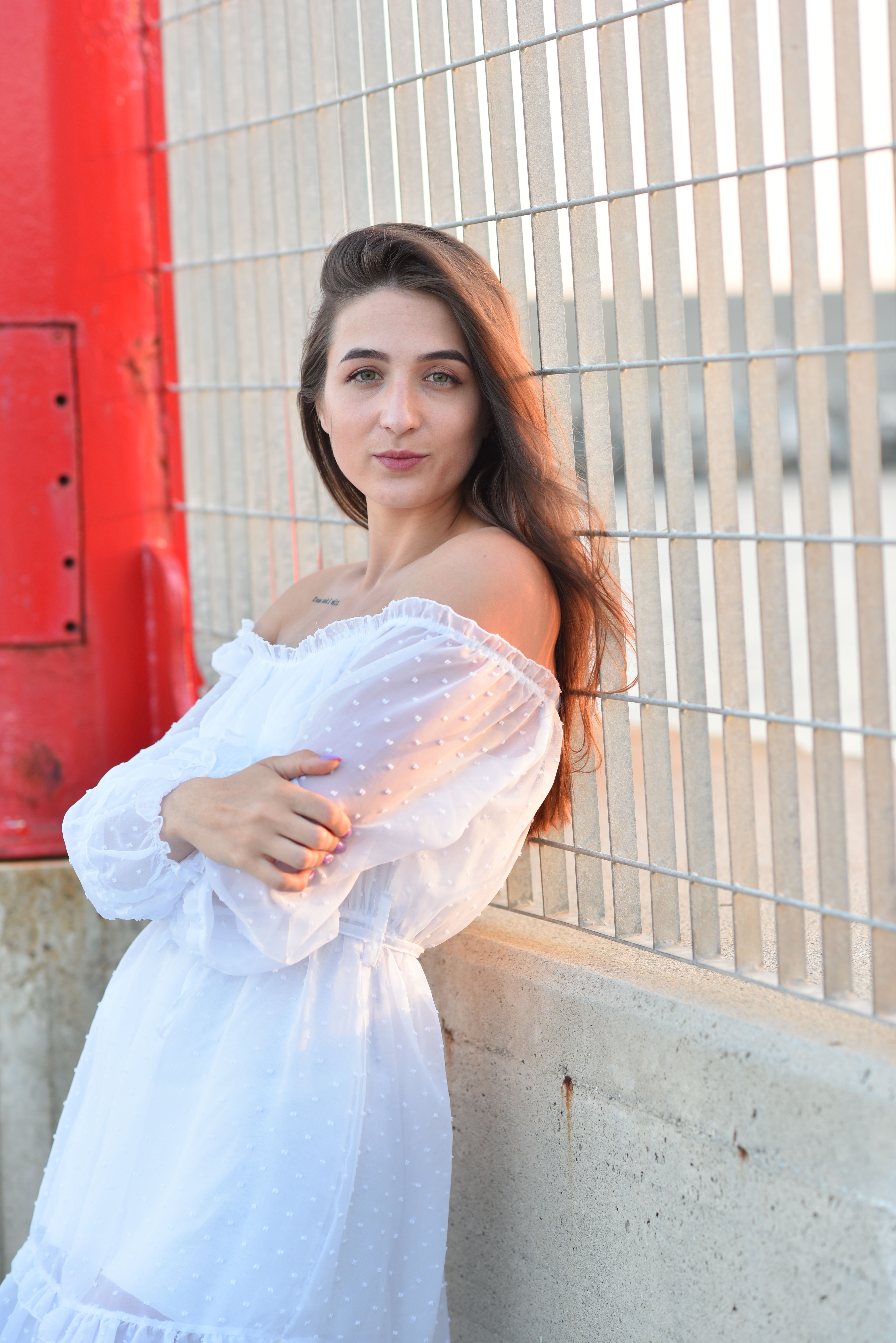 Young Woman in a White Dress Standing against a Fence · Free Stock Photo