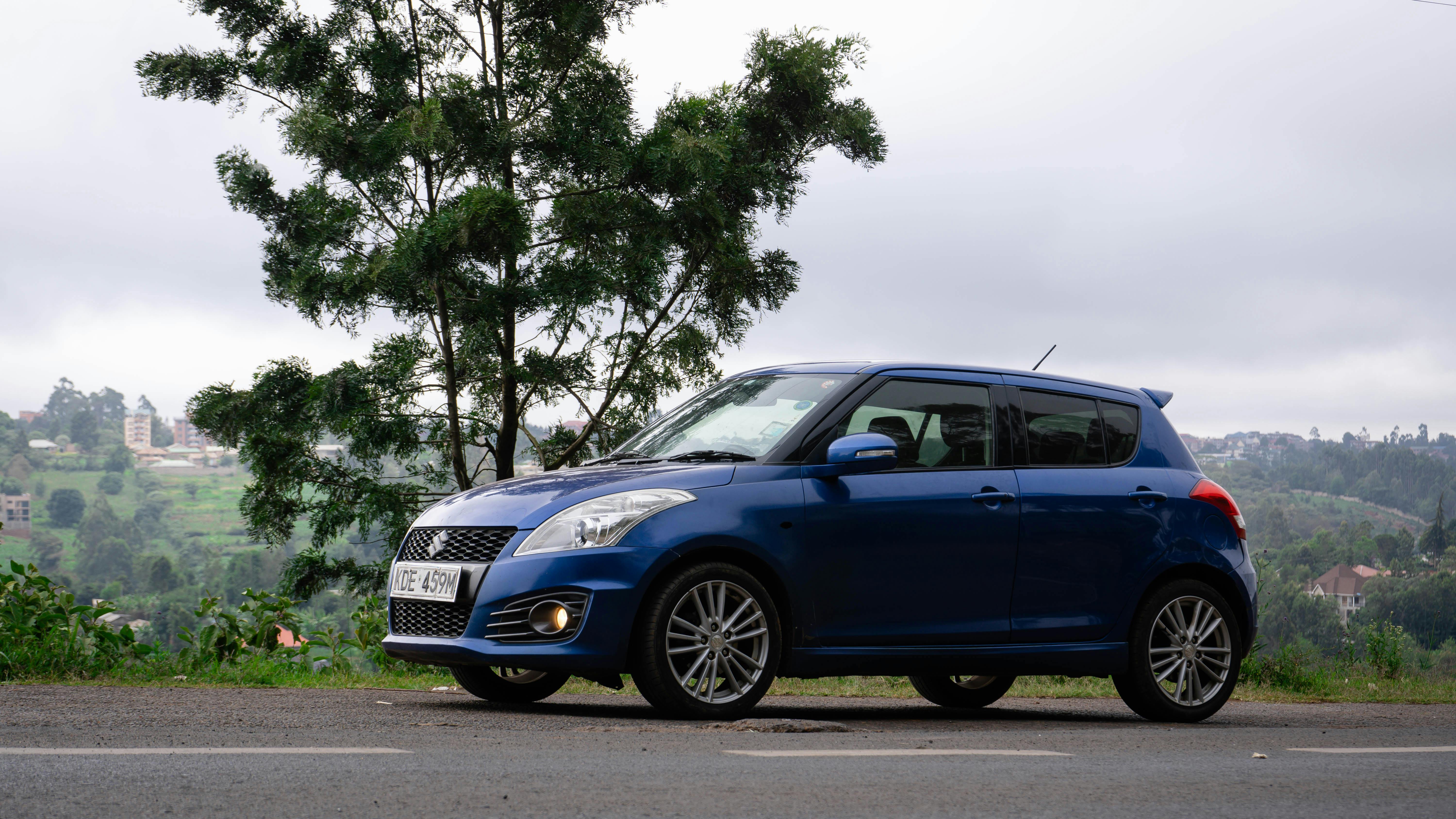 Blue Suzuki Swift Car on a Hill Road · Free Stock Photo