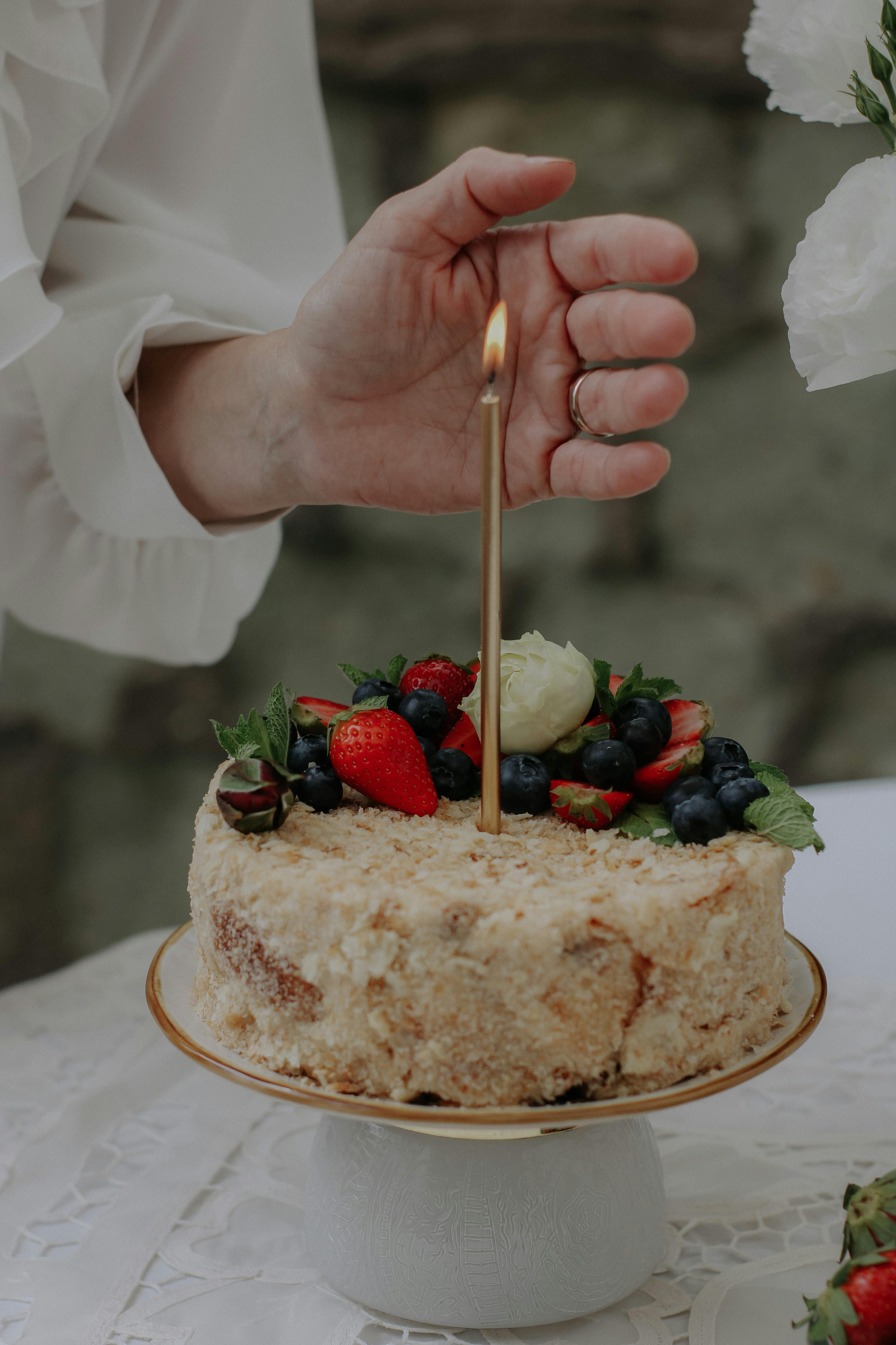 Hand over Candle in Cake · Free Stock Photo