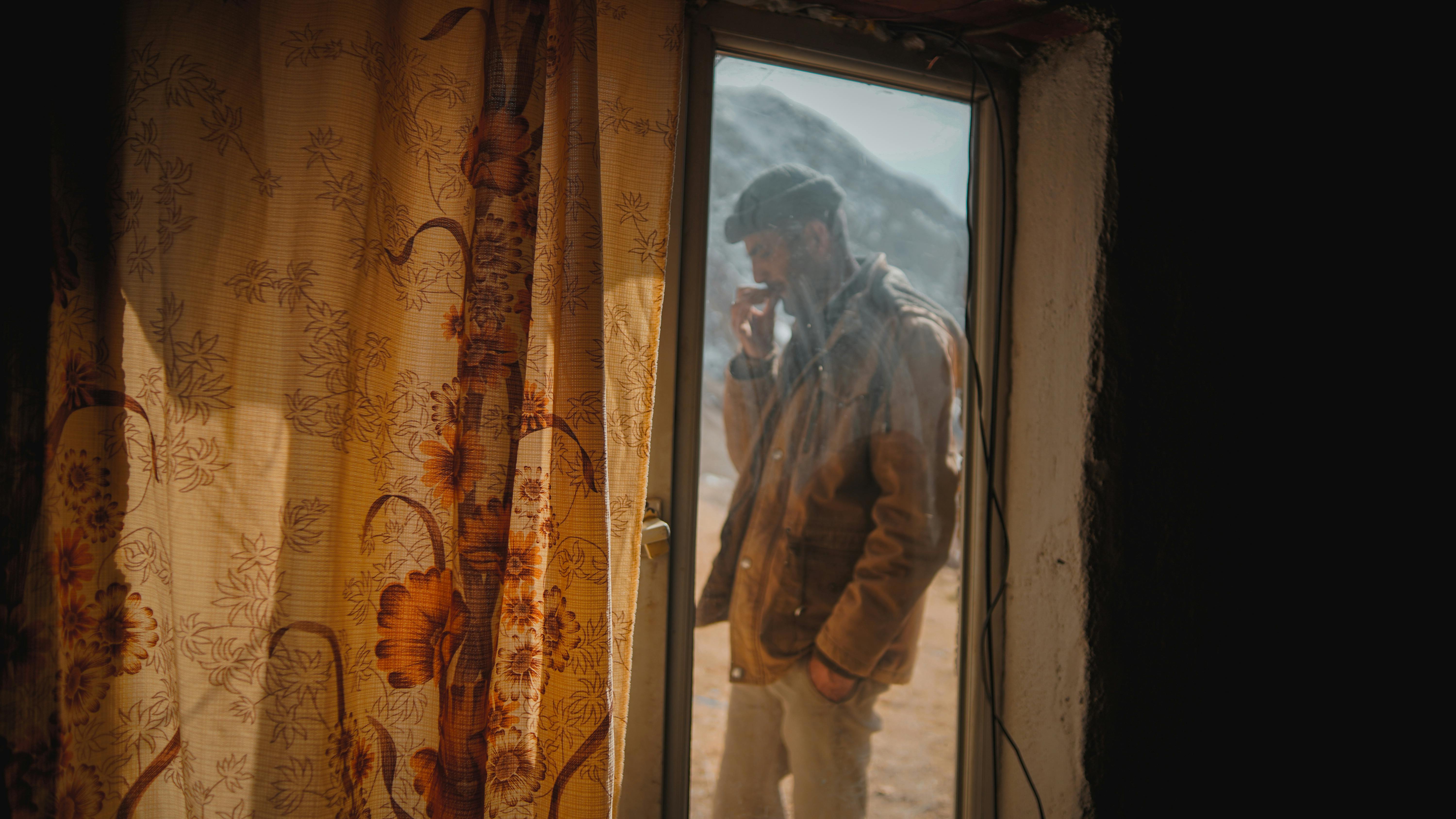 A Man Photographed from the Inside of a Vintage House Standing Outside ...
