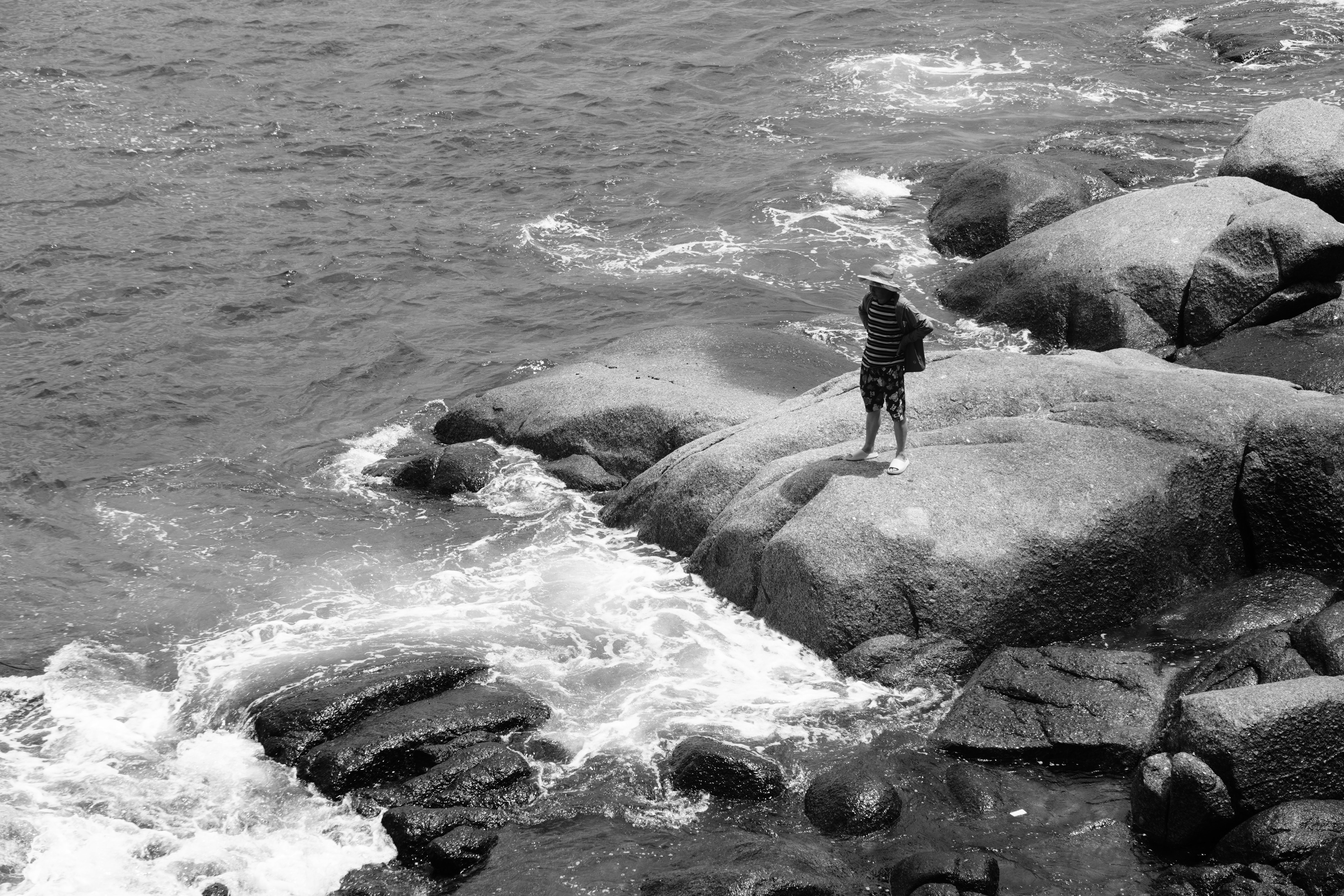 Person Standing on Rocks on Sea Shore · Free Stock Photo