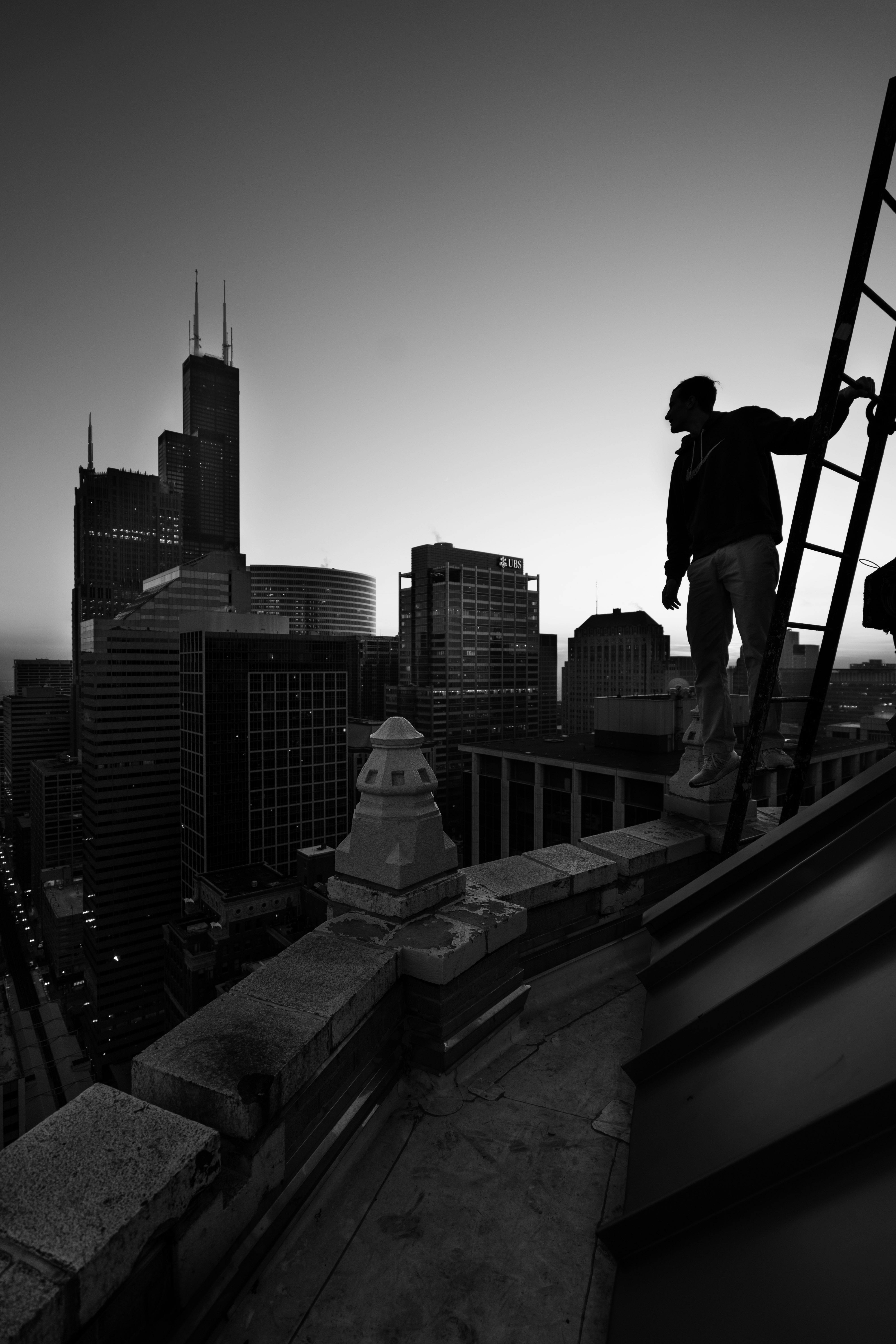 Man Standing On Building While Holding Ladder · Free Stock Photo