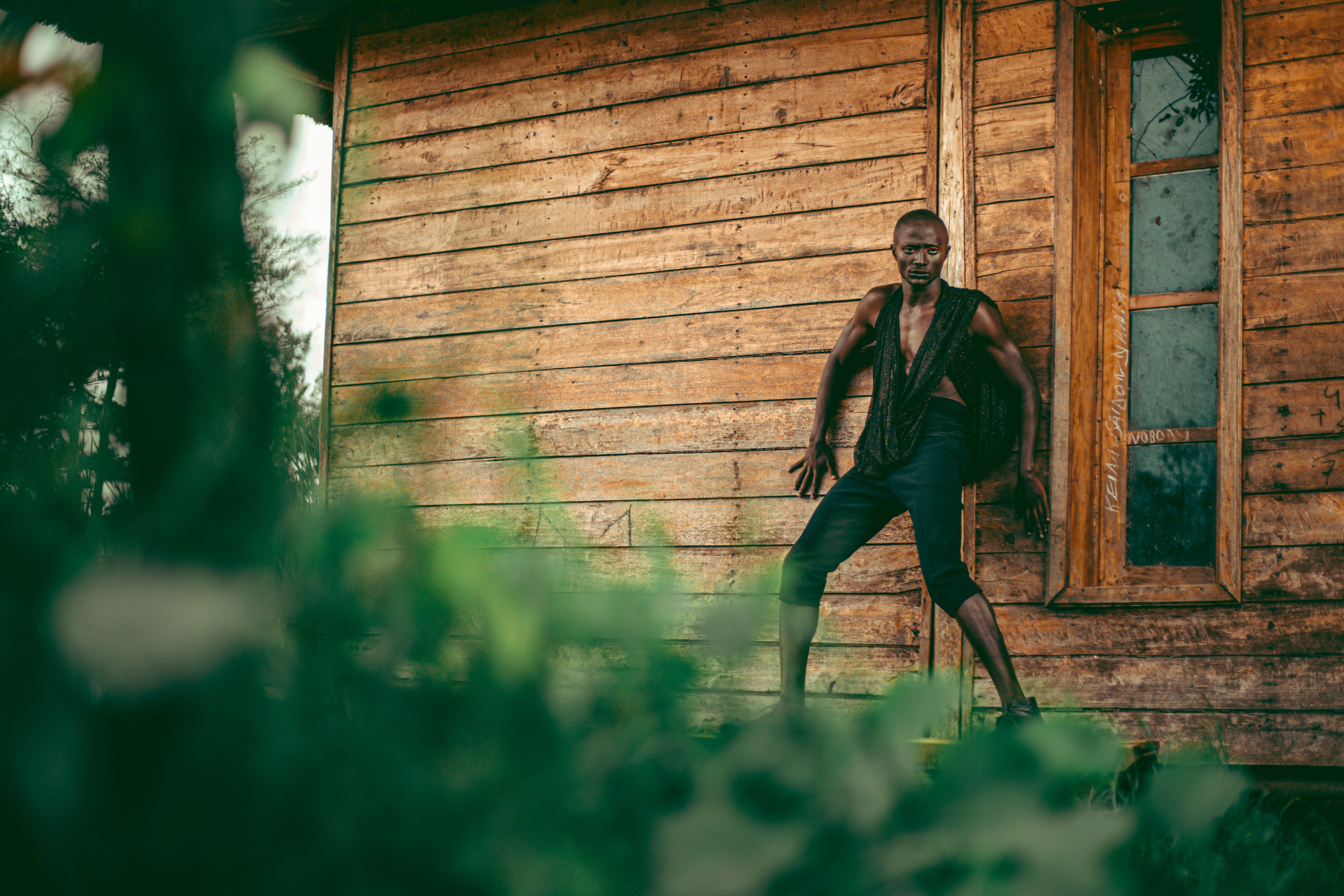 Man Standing by Wooden Cottage Wall · Free Stock Photo
