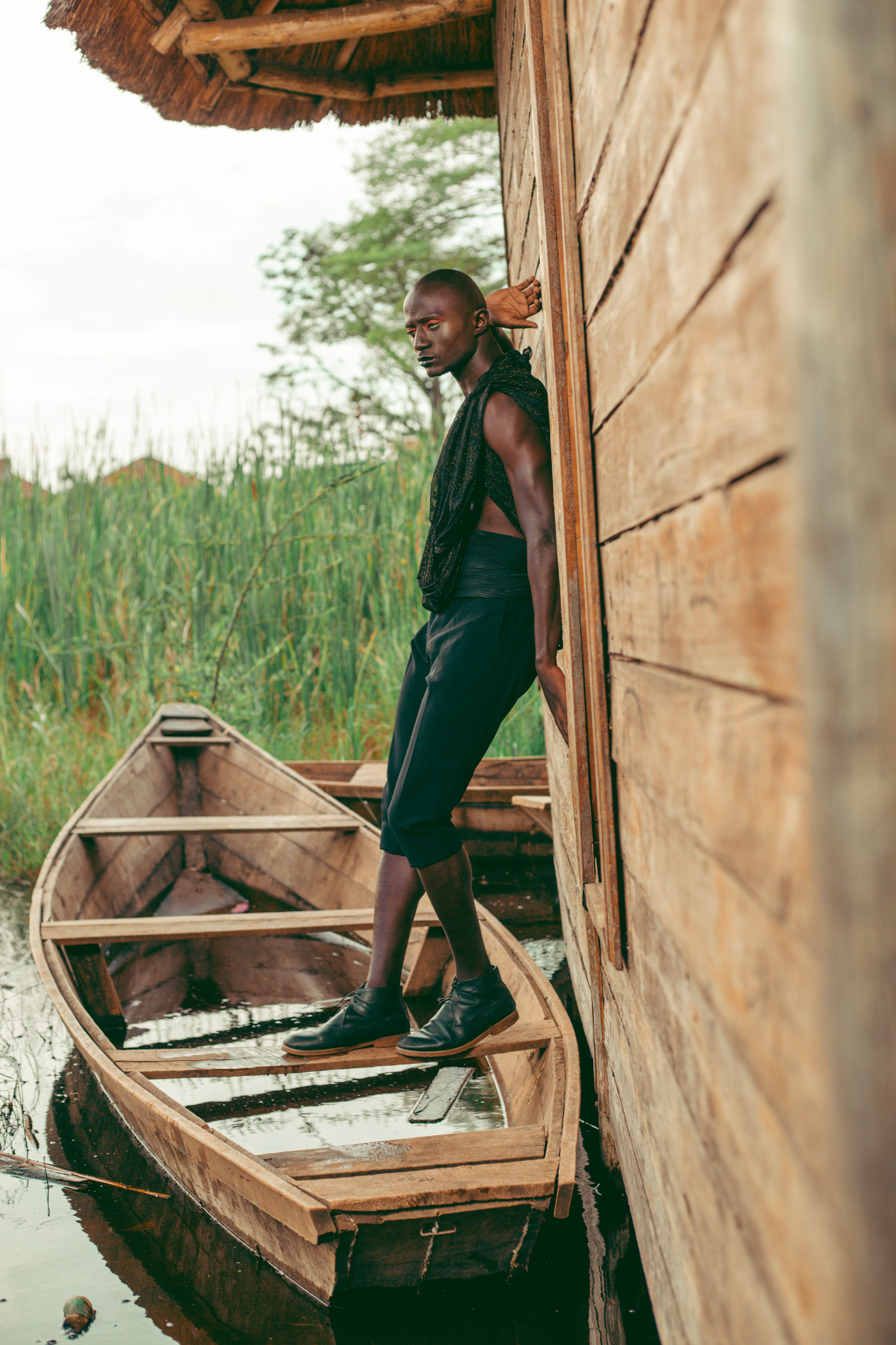 Man Standing on Boat and Leaning on Cottage Wall · Free Stock Photo