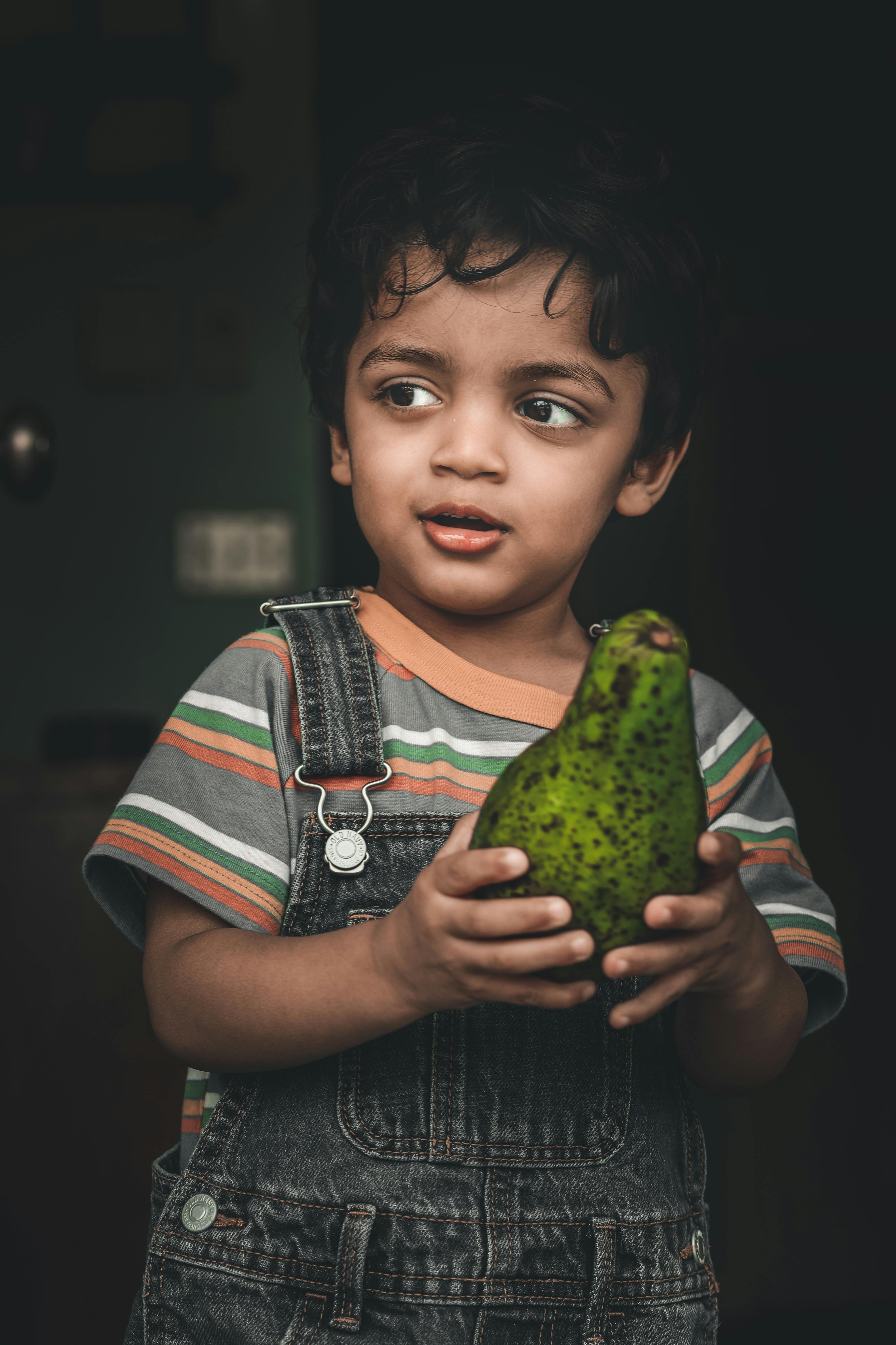 A Little Boy Holding an Avocado · Free Stock Photo