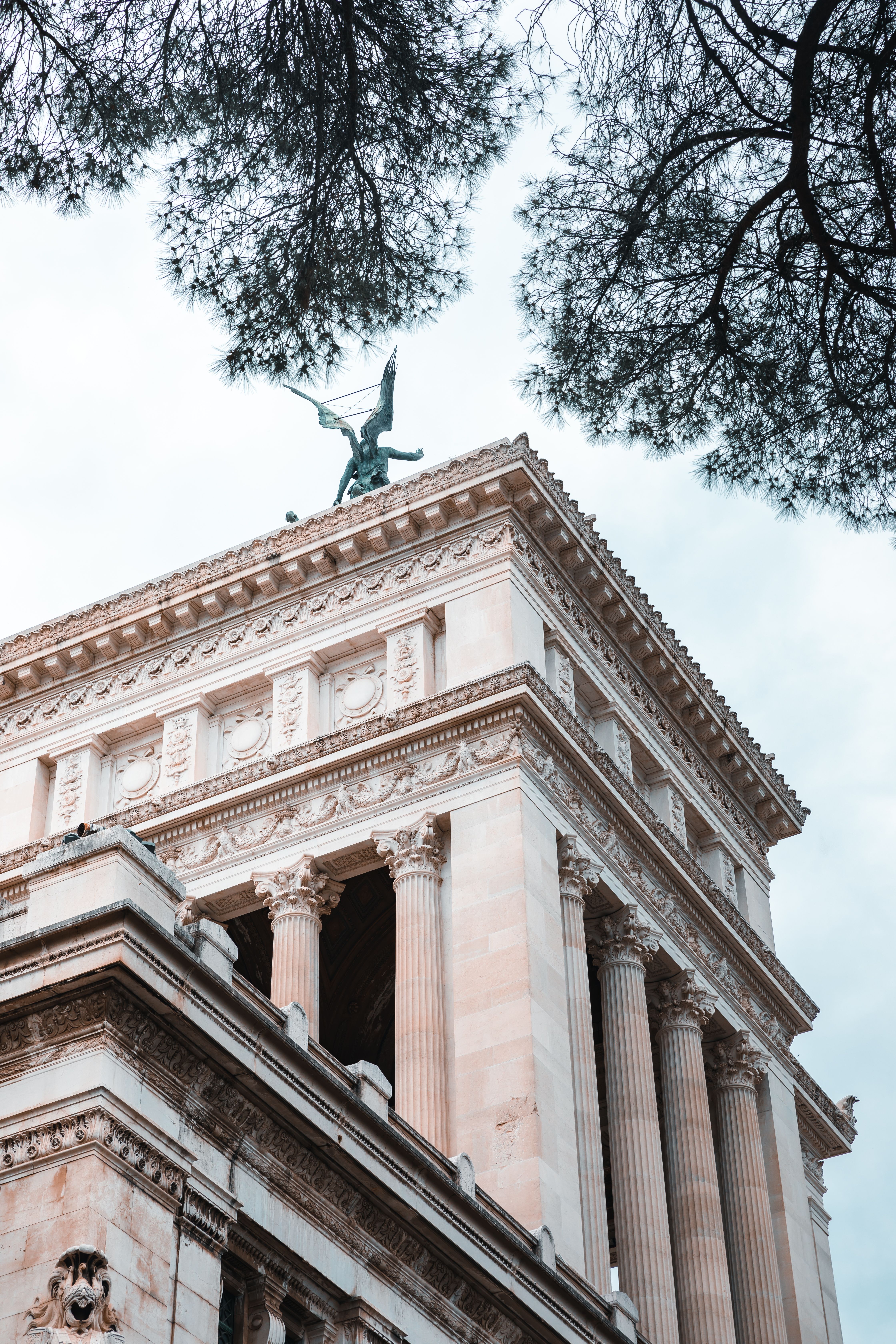 A building with a statue on top and a tree in the background · Free ...