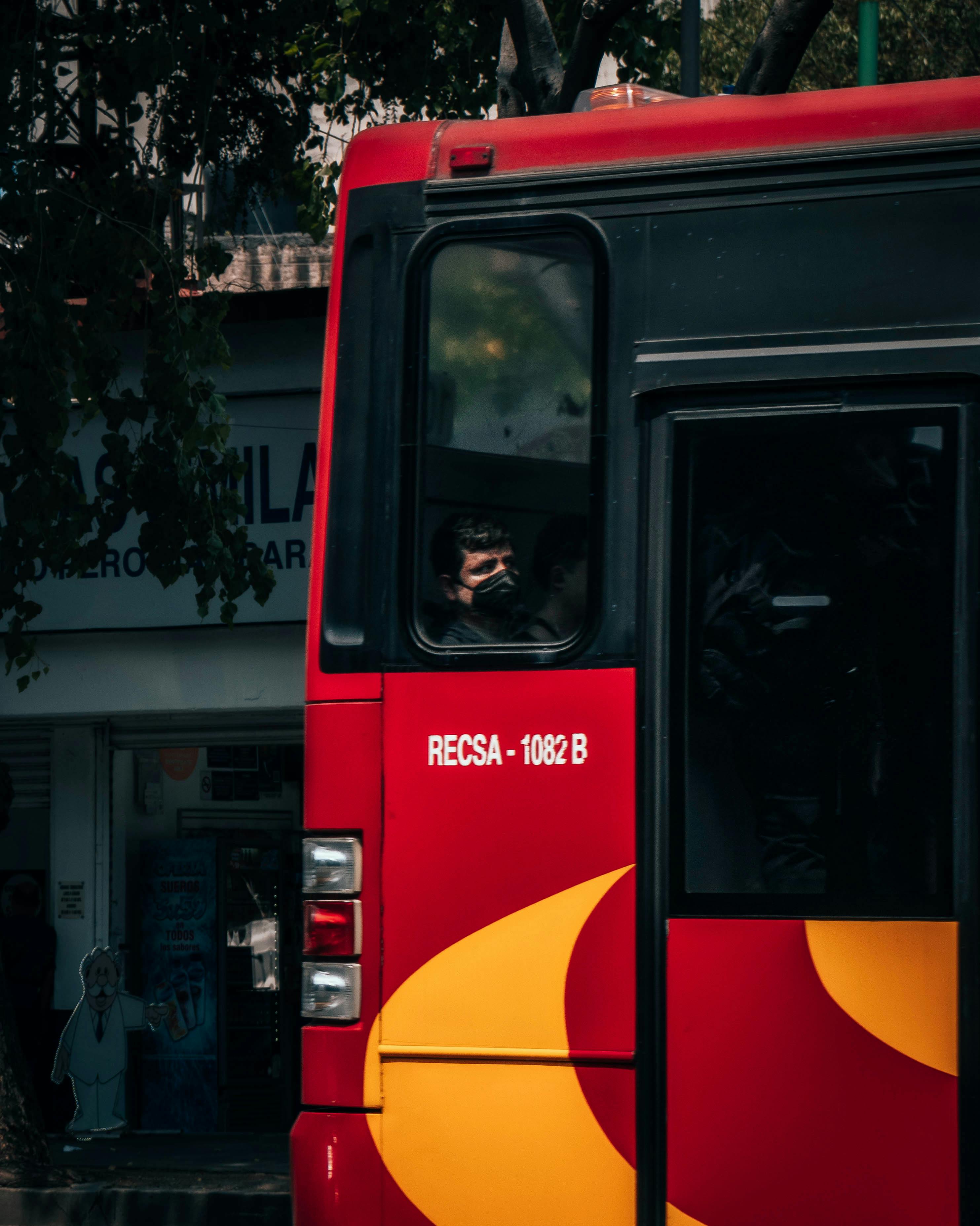 A red and yellow bus with a man taking a picture · Free Stock Photo